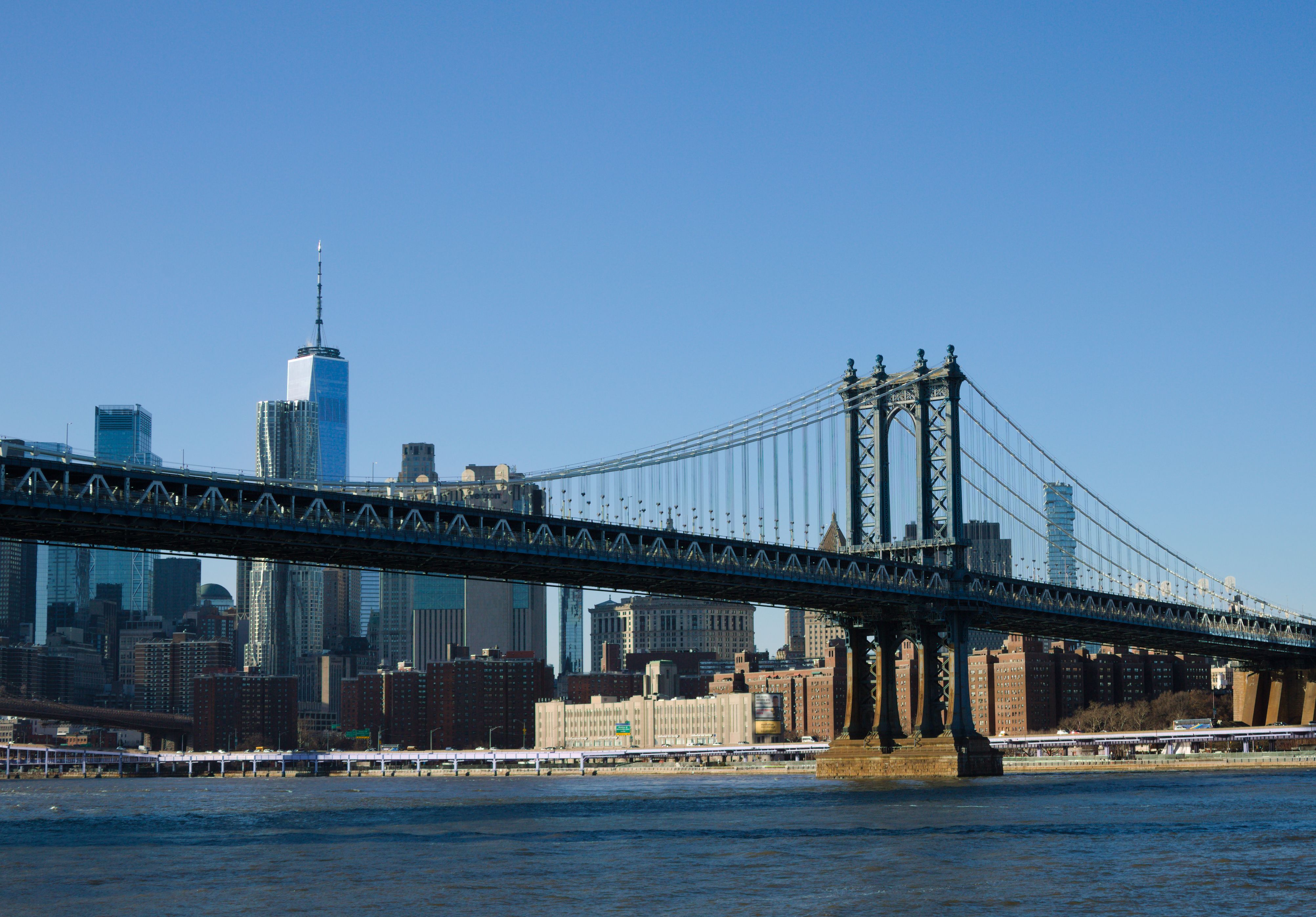 The manhattan bridge is seen from the water · Free Stock Photo