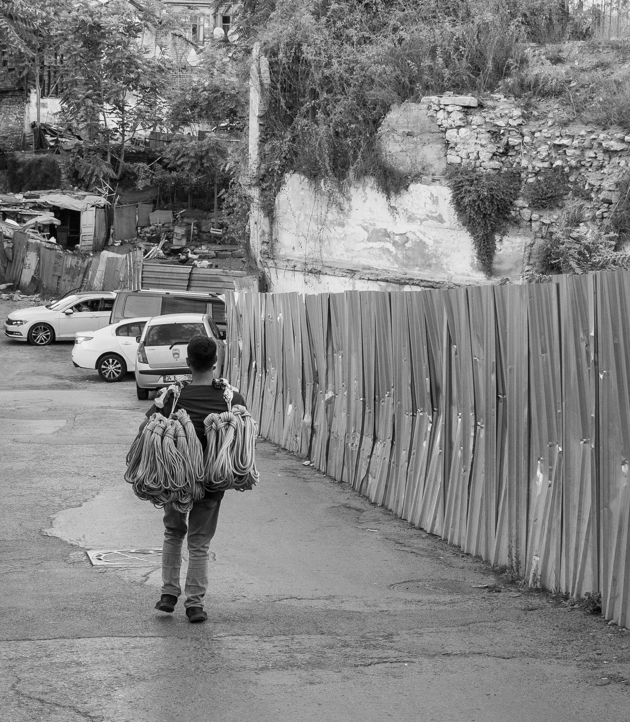 Back View of a Man Carrying Ropes on a Street · Free Stock Photo