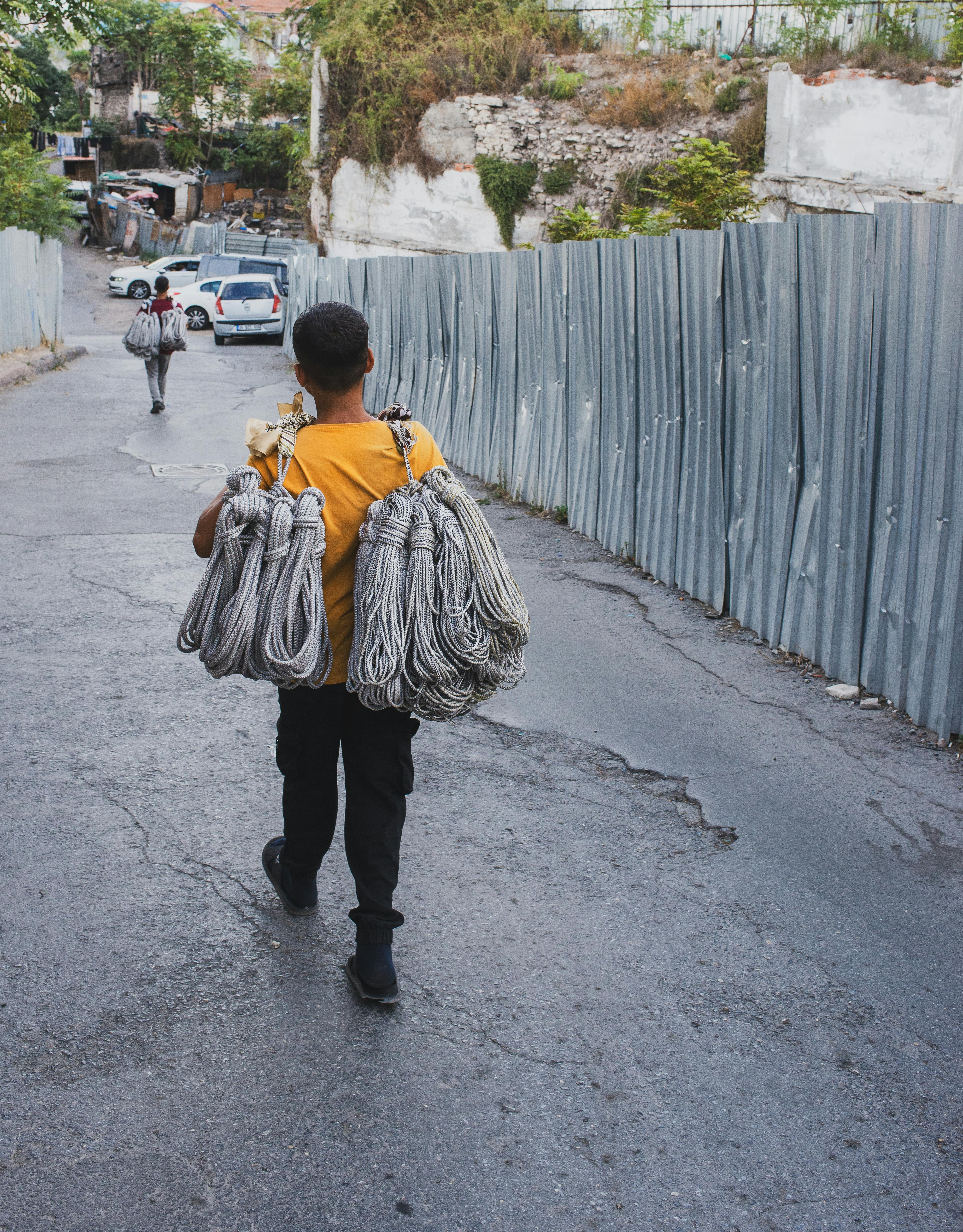 Back View of a Man Carrying Ropes on a Street · Free Stock Photo