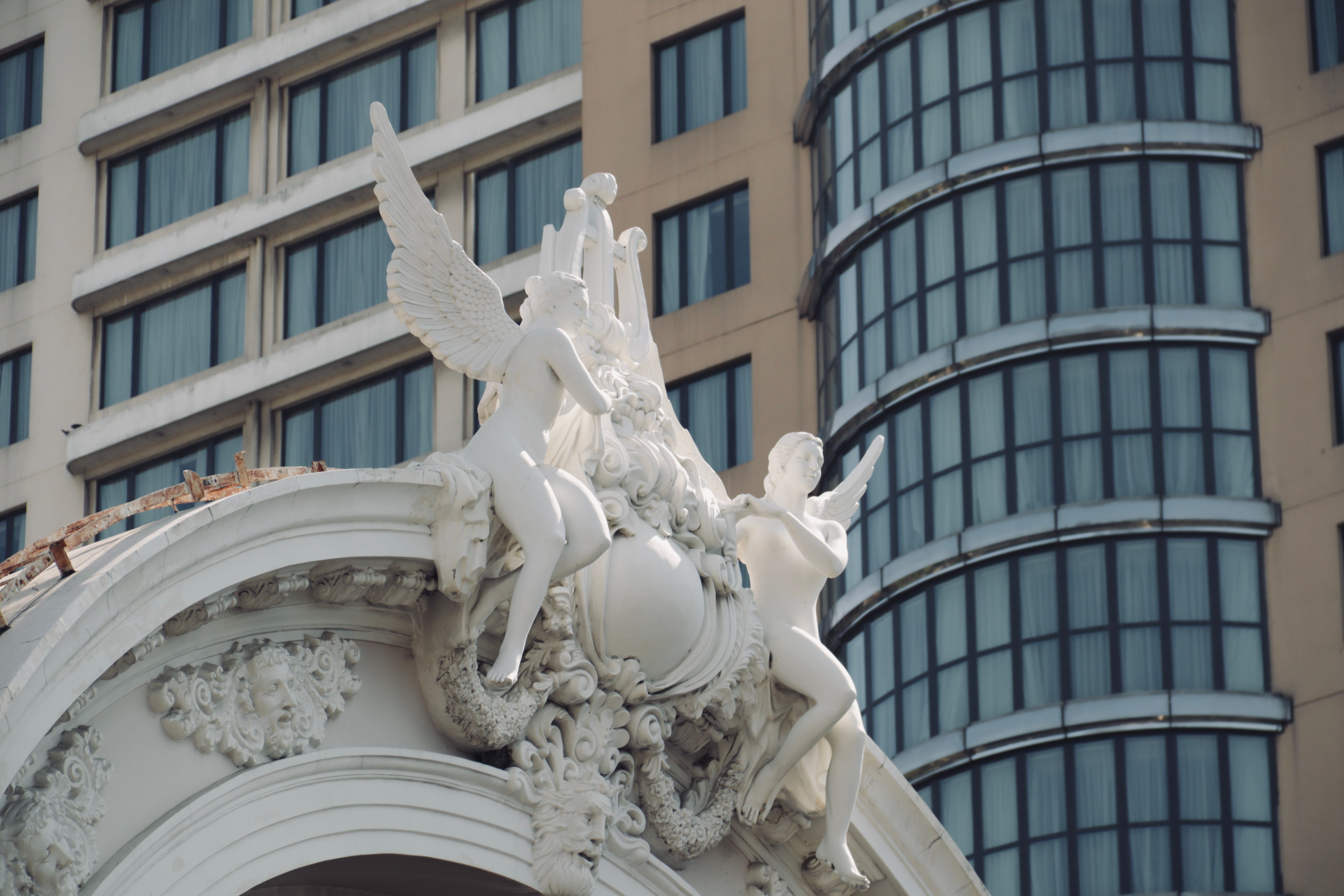 Close-up of a Statue on Top of a Building on the Background of a Modern ...