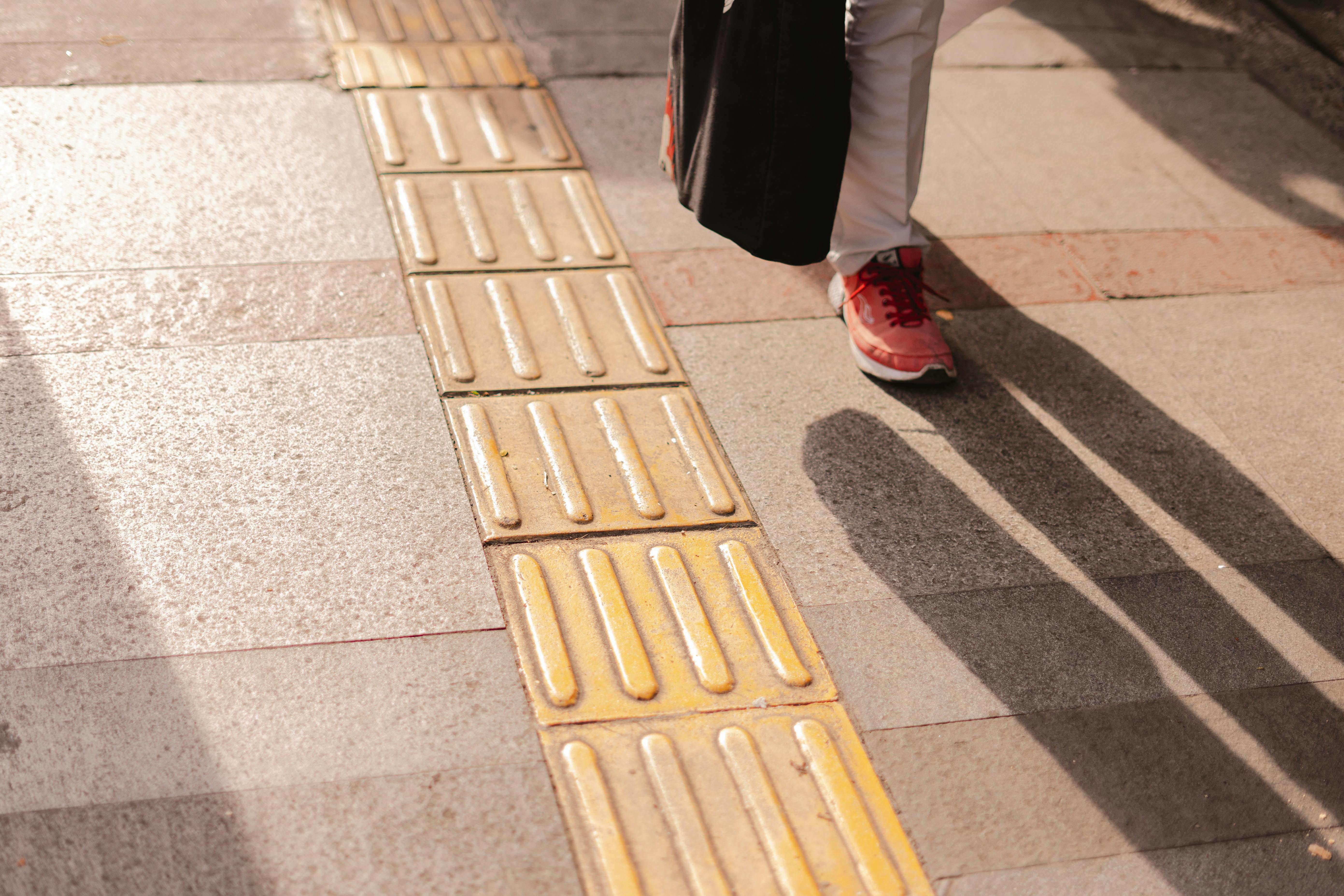 People walking on pedestrian sidewalk alone · Free Stock Photo