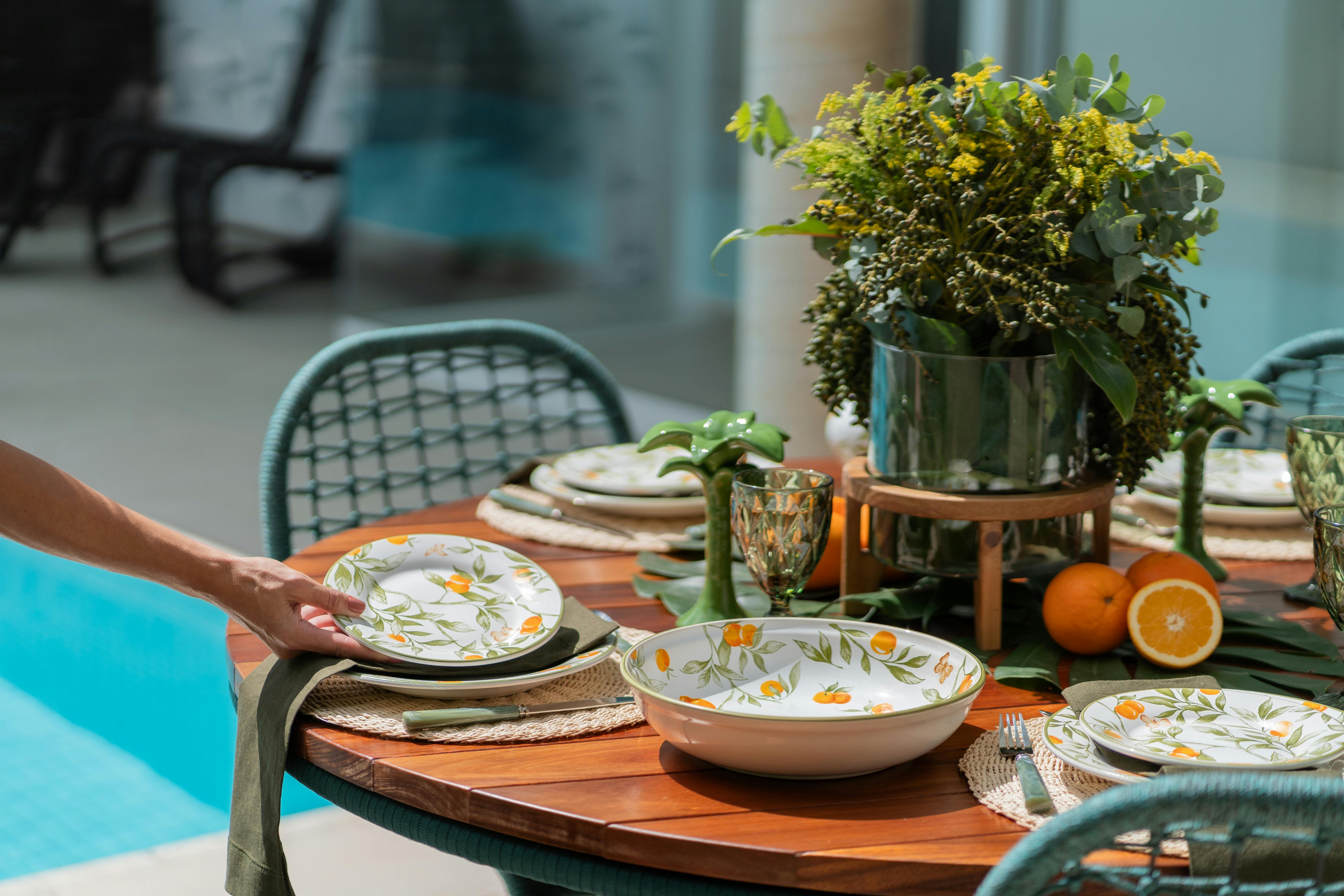 Woman Hand Holding Plates over Table · Free Stock Photo