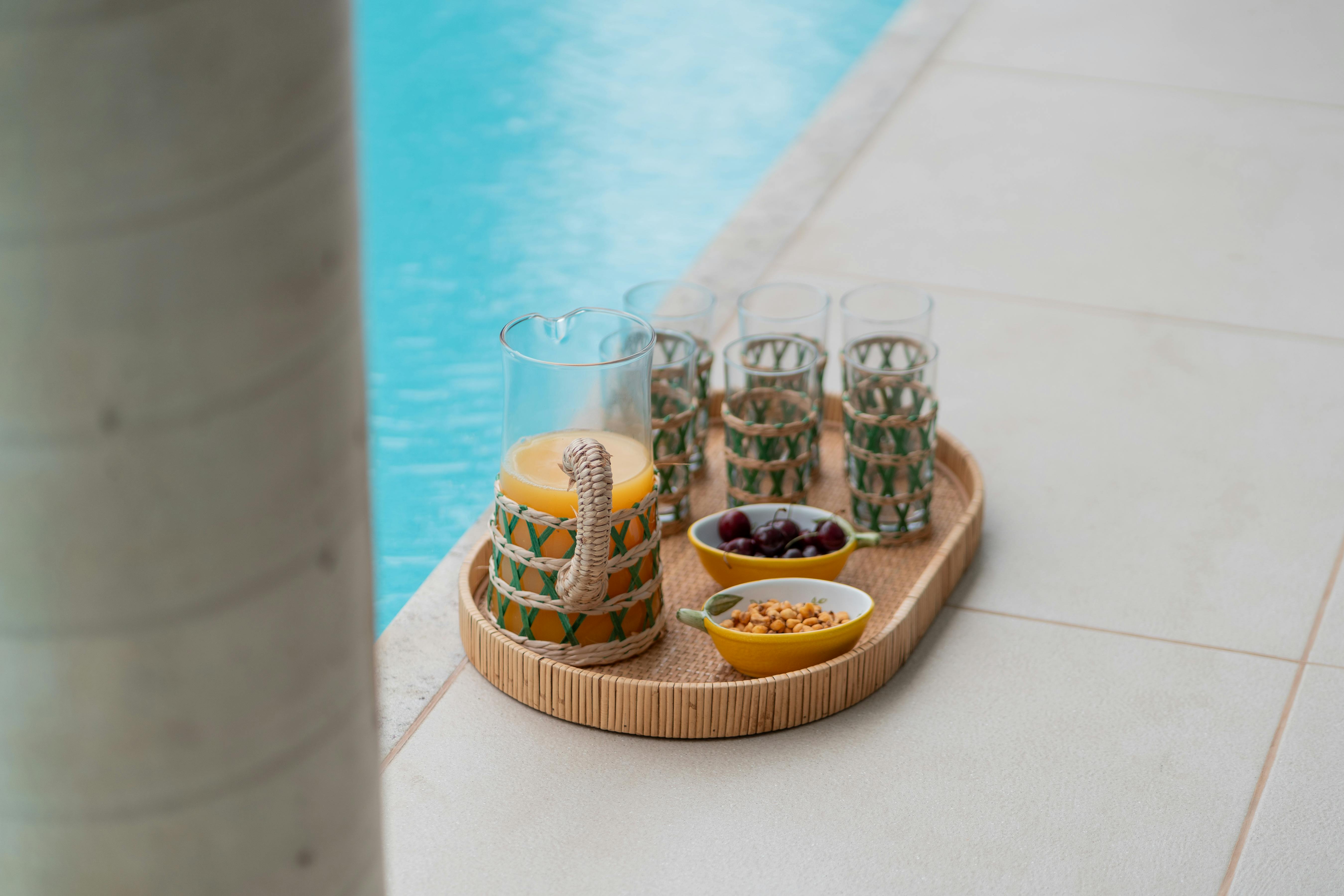 Colorful Orange Juice Carafe with Glasses and Snack Tray near the Pool ...