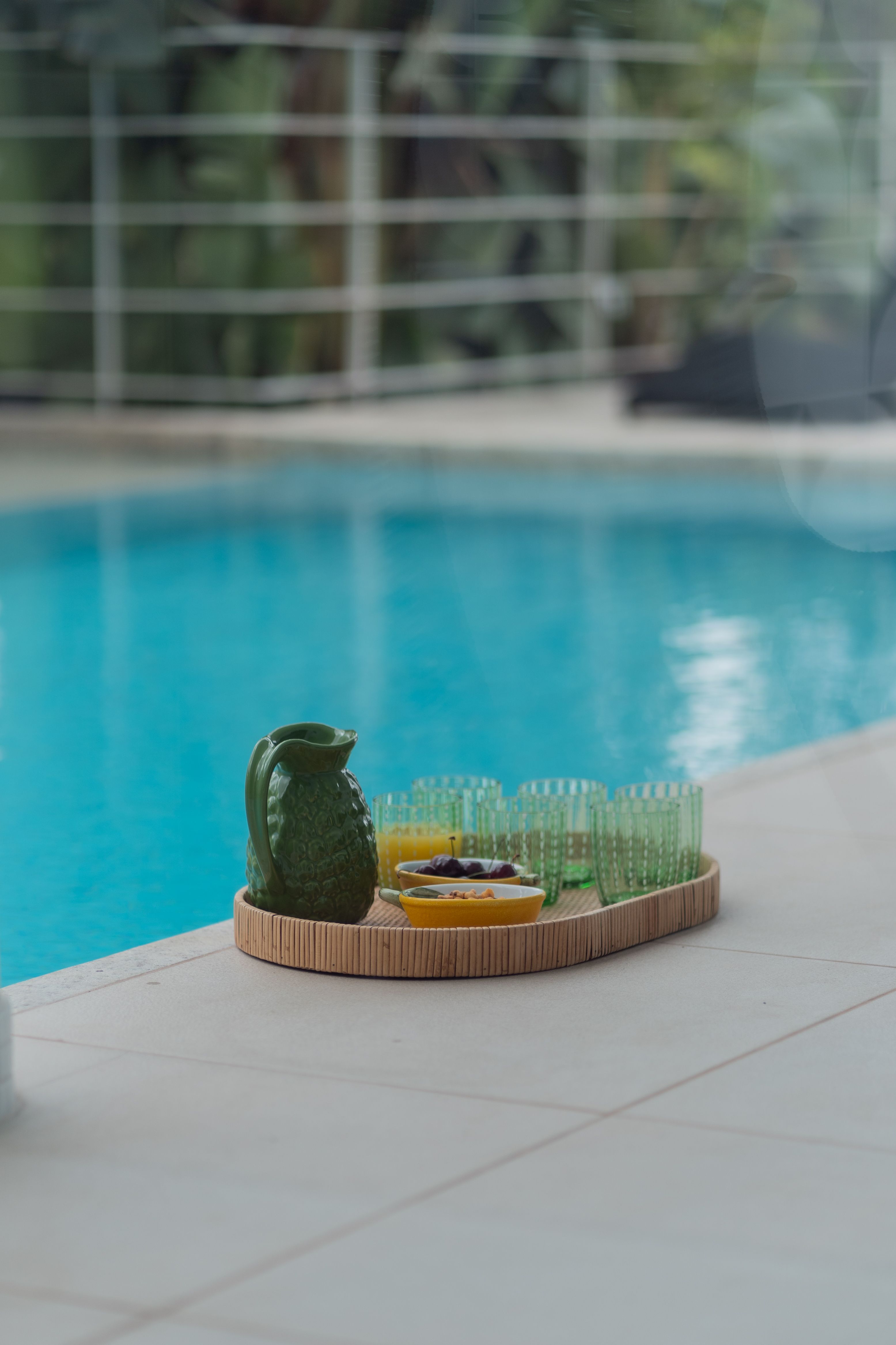 A tray with a drink and a glass on the edge of a pool · Free Stock Photo