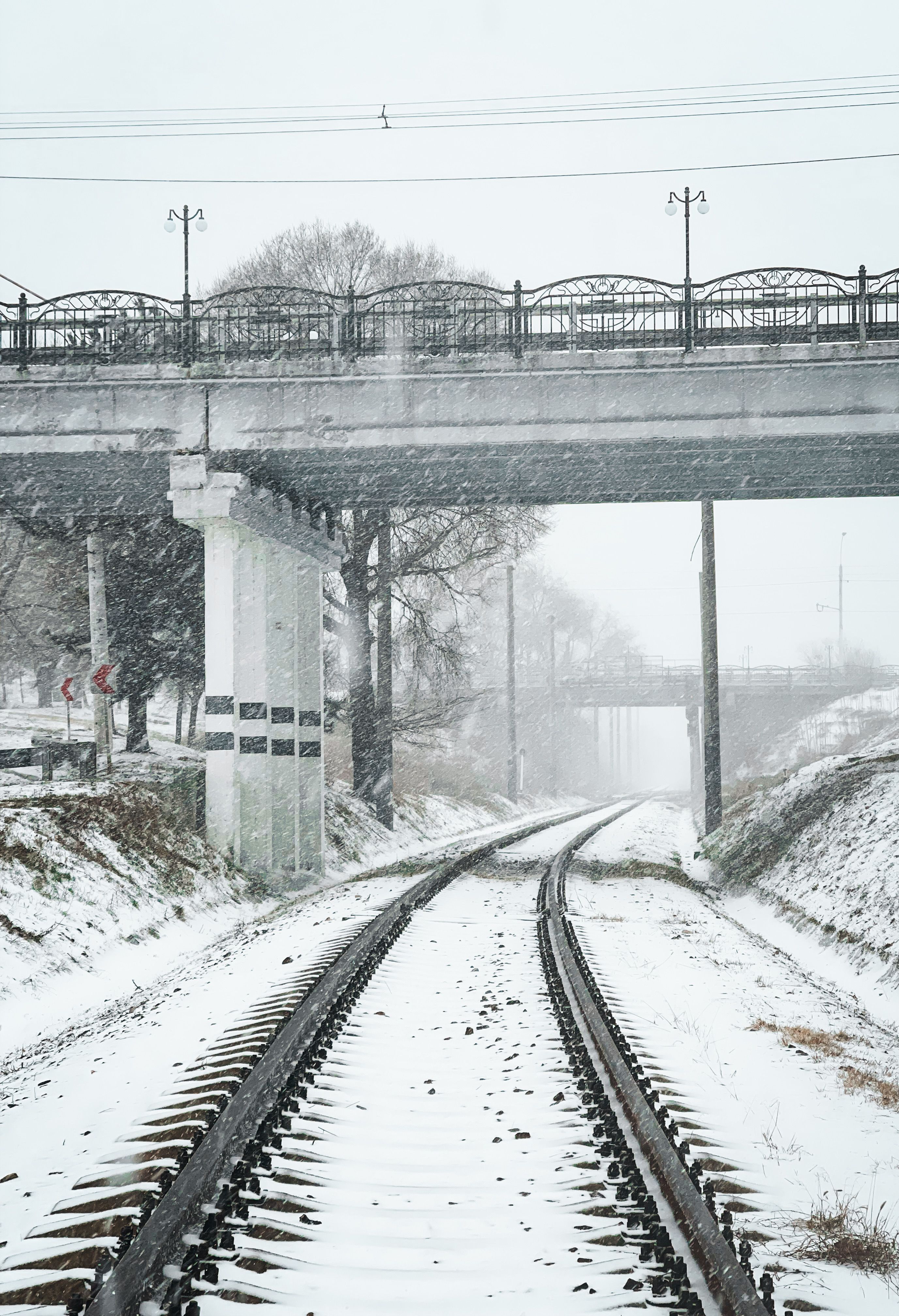 A train track in the snow under an overpass · Free Stock Photo