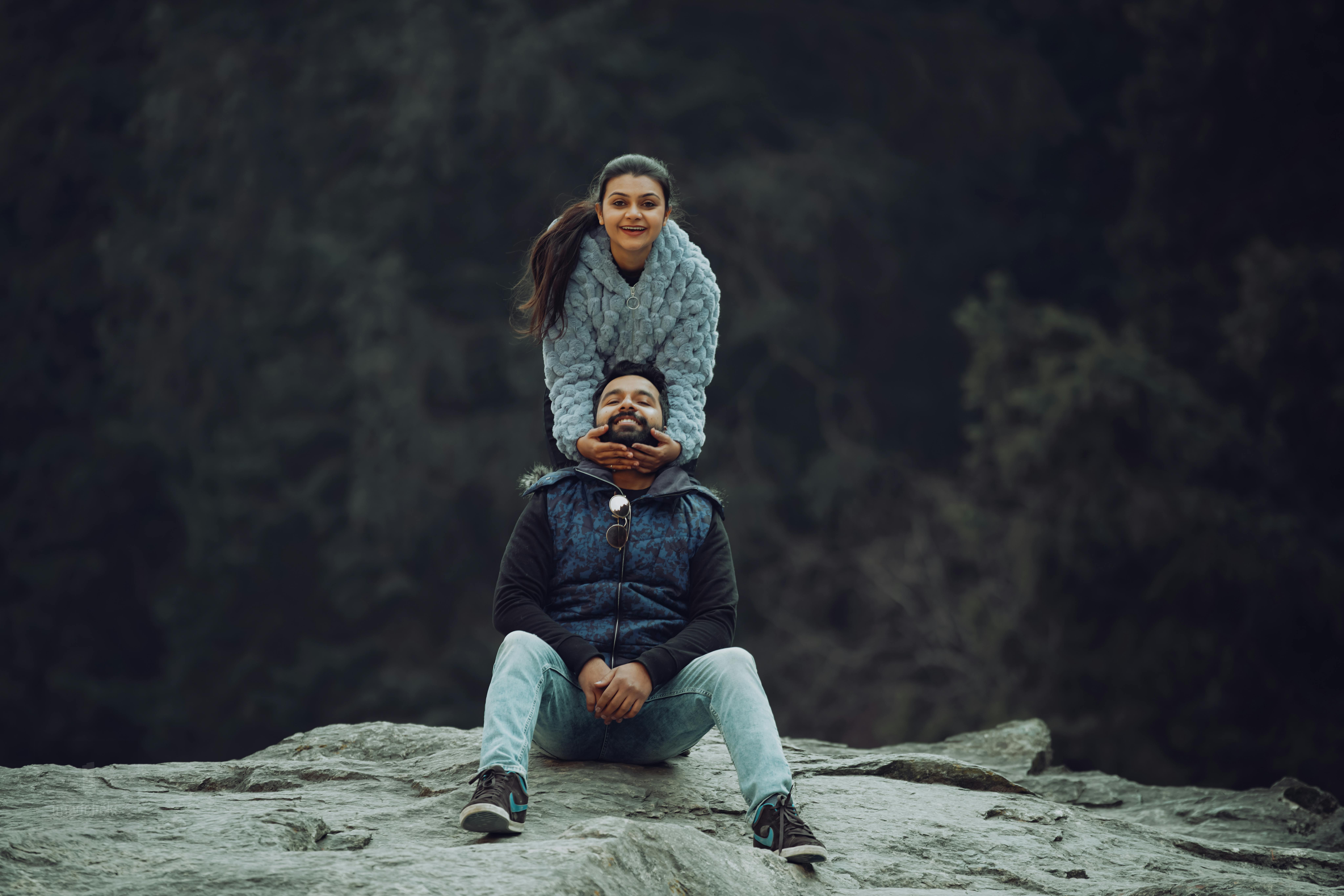 Smiling Woman Standing over Man Sitting on Rocks · Free Stock Photo
