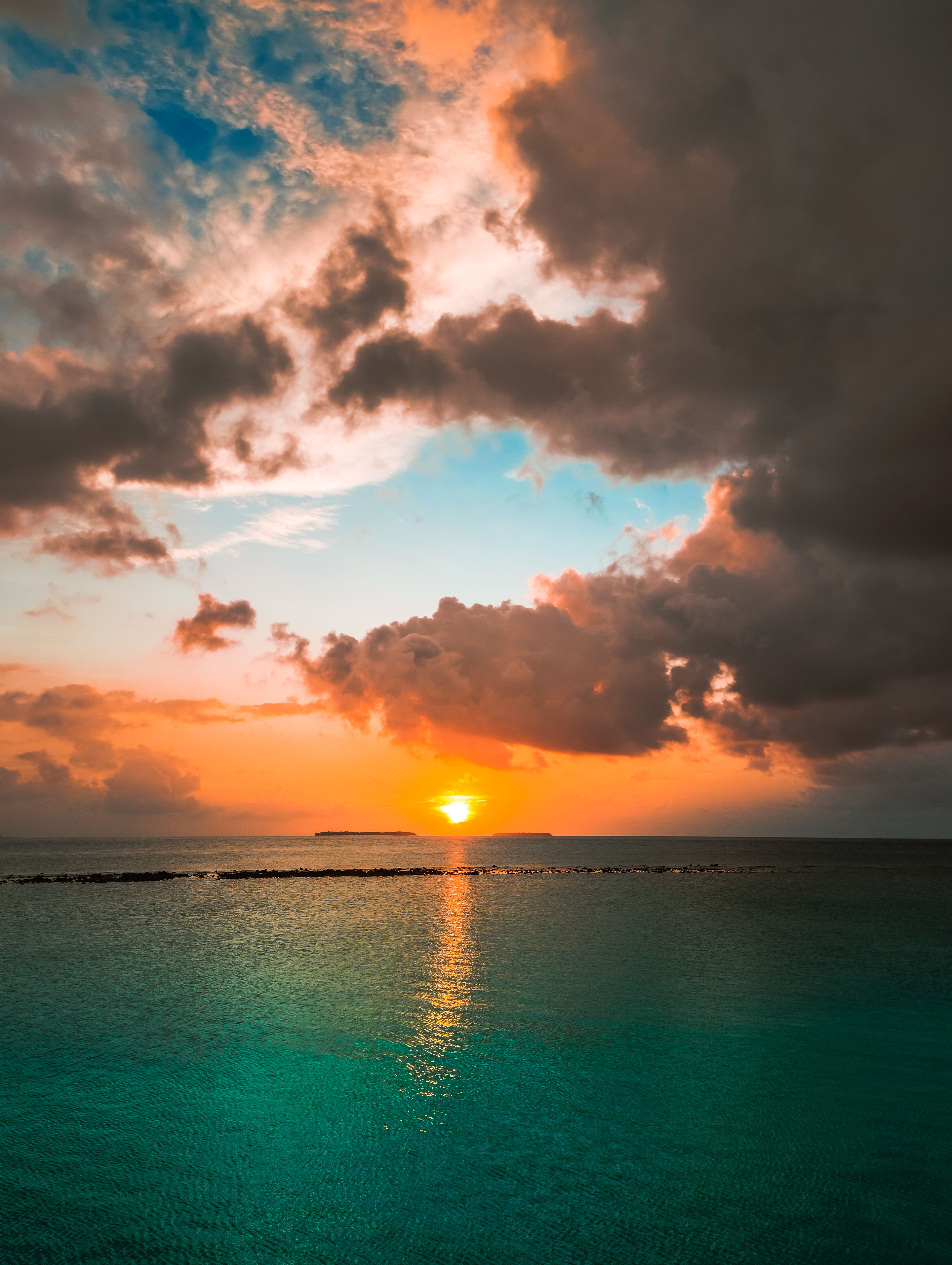 A sunset over the ocean with clouds and water · Free Stock Photo