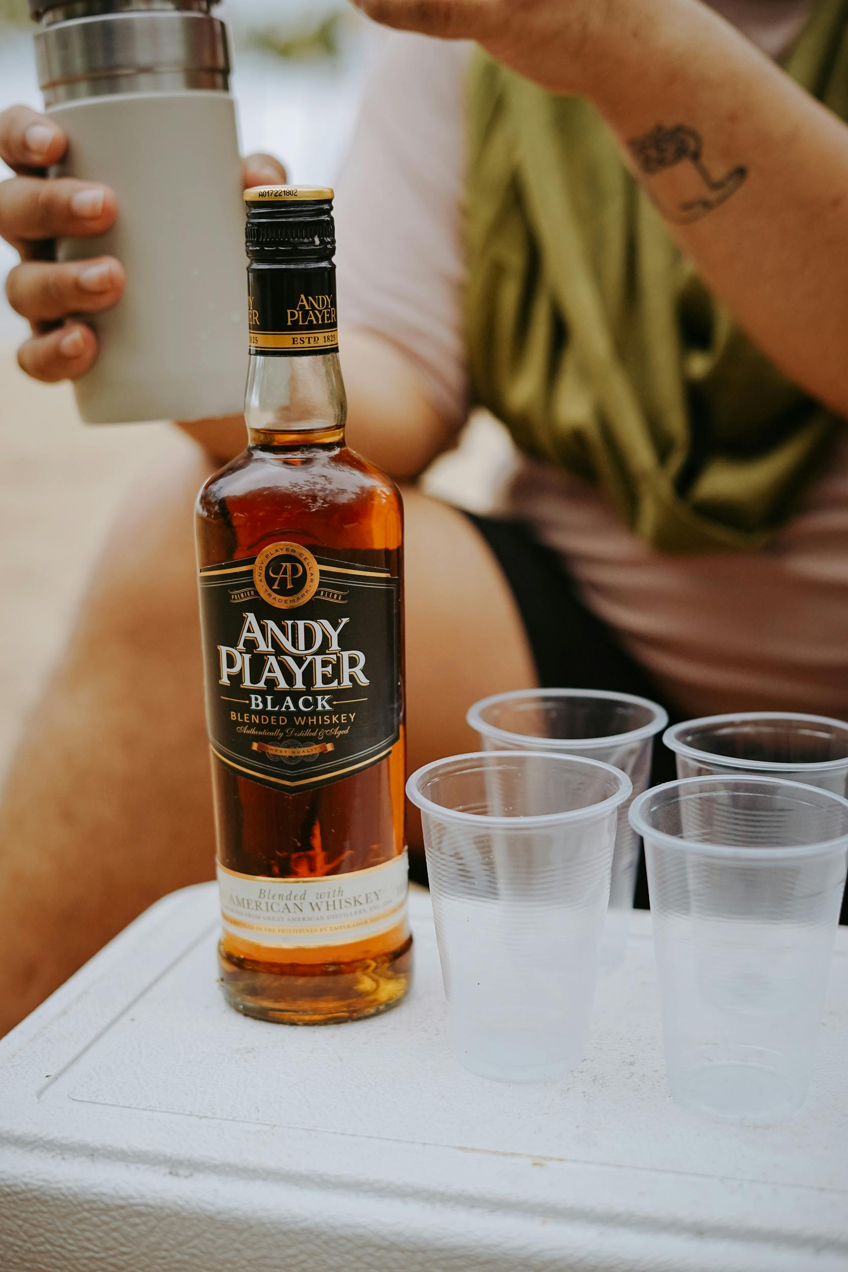 Andy Player Black Whiskey Bottle and Disposable Cups · Free Stock Photo