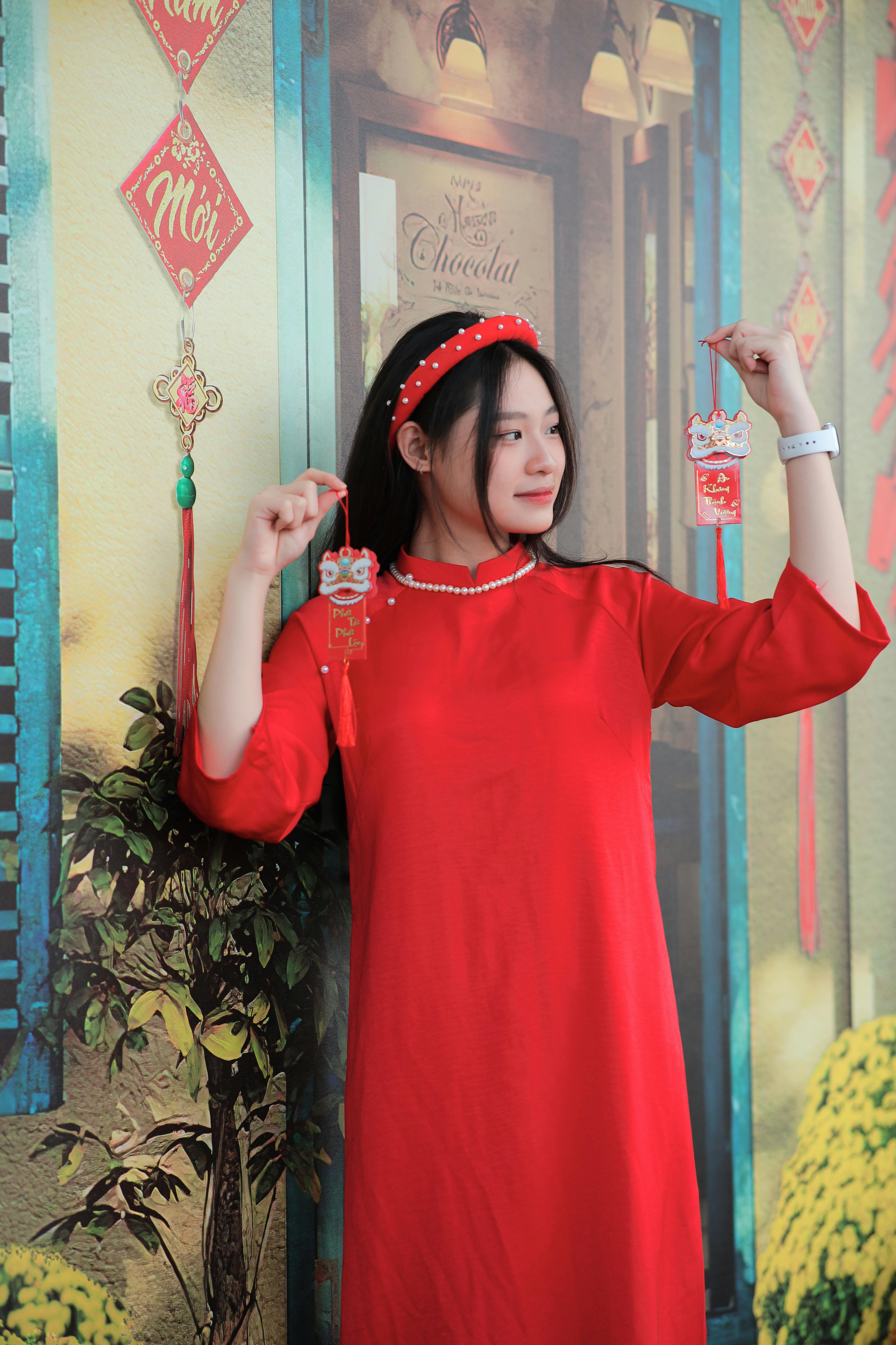 Young Model in Red Ao Dai Tunic and Headband Looking at Charms · Free ...