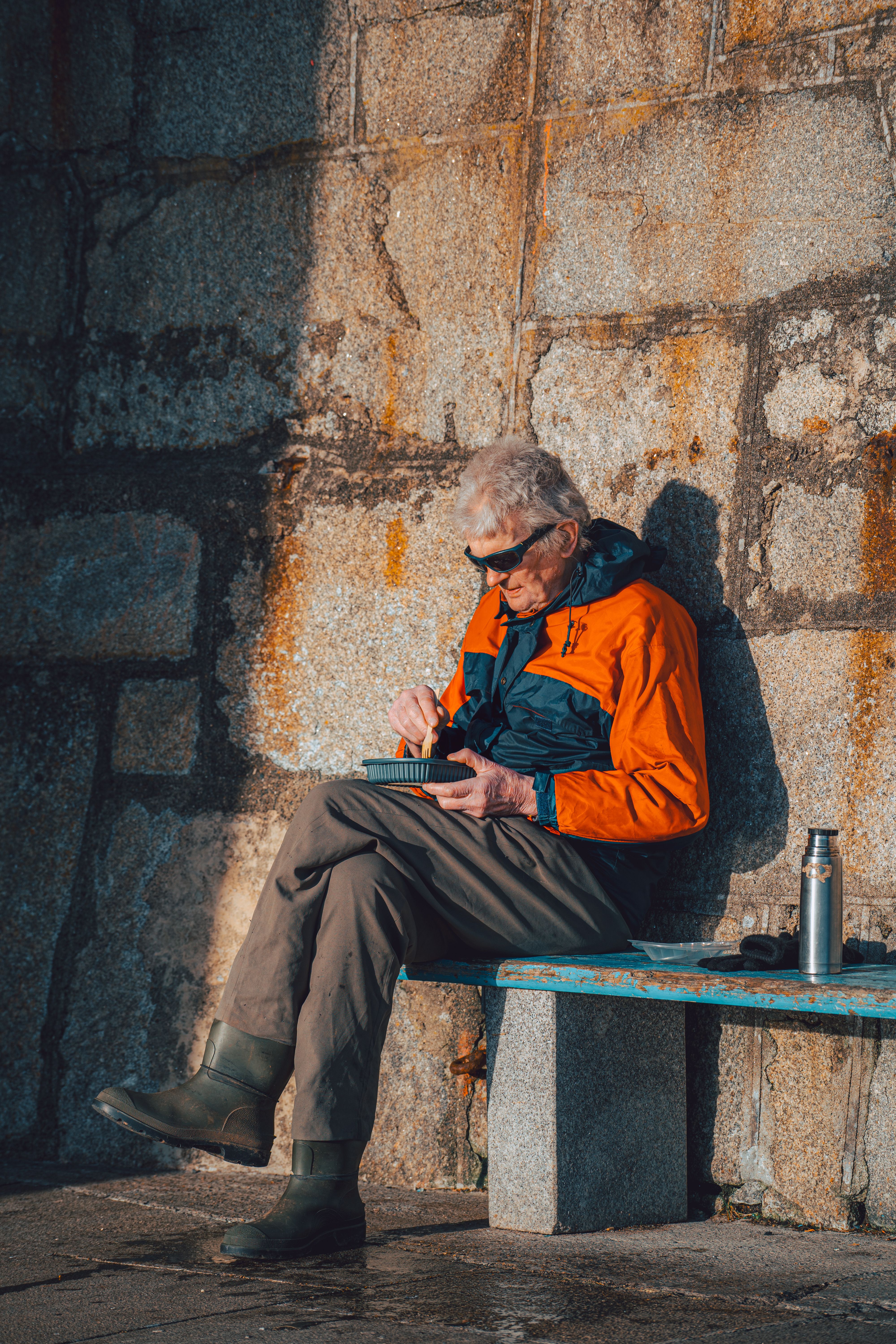 Man Wearing Orange Jacket Sitting by the Street · Free Stock Photo