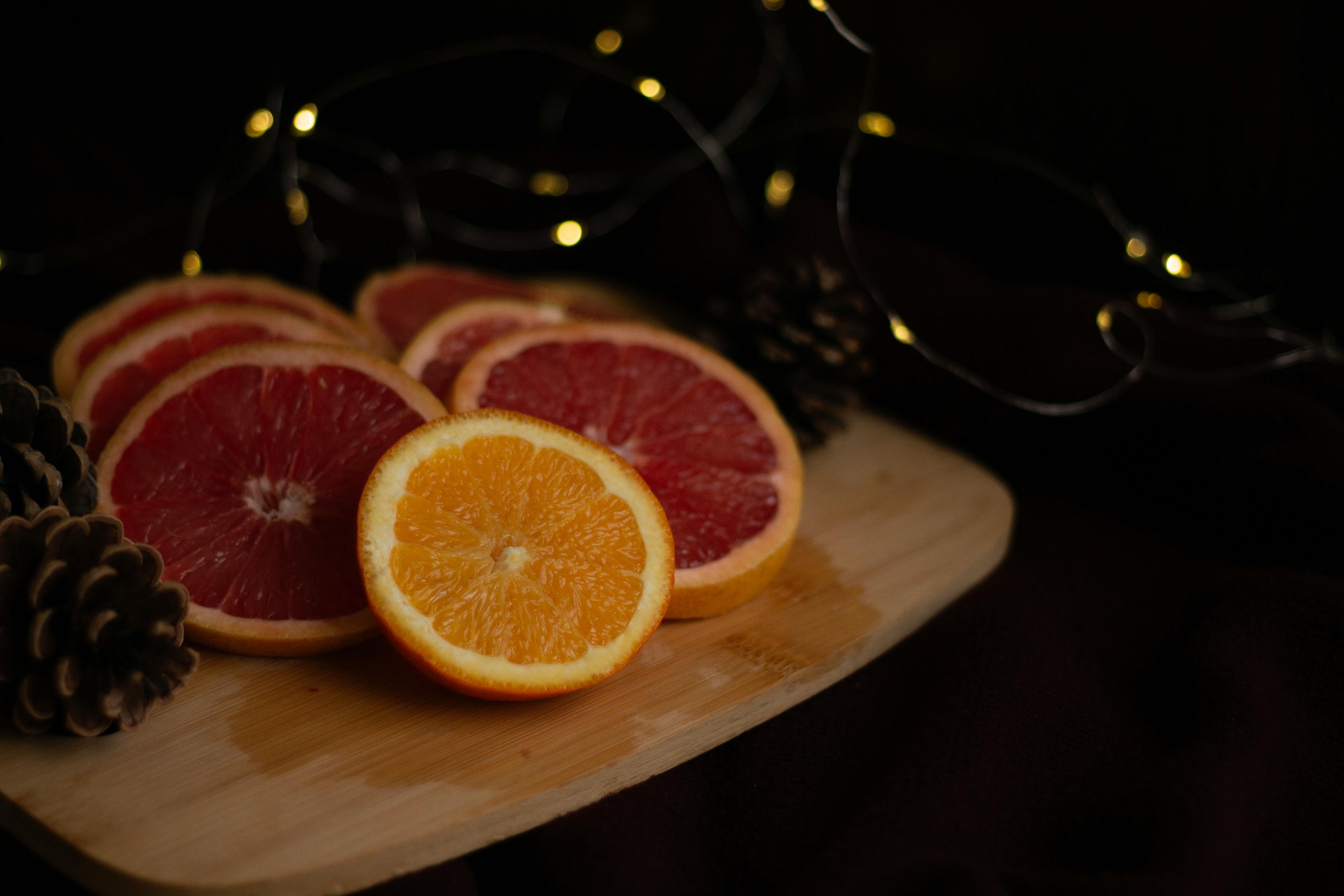 A wooden cutting board with oranges and pine cones · Free Stock Photo