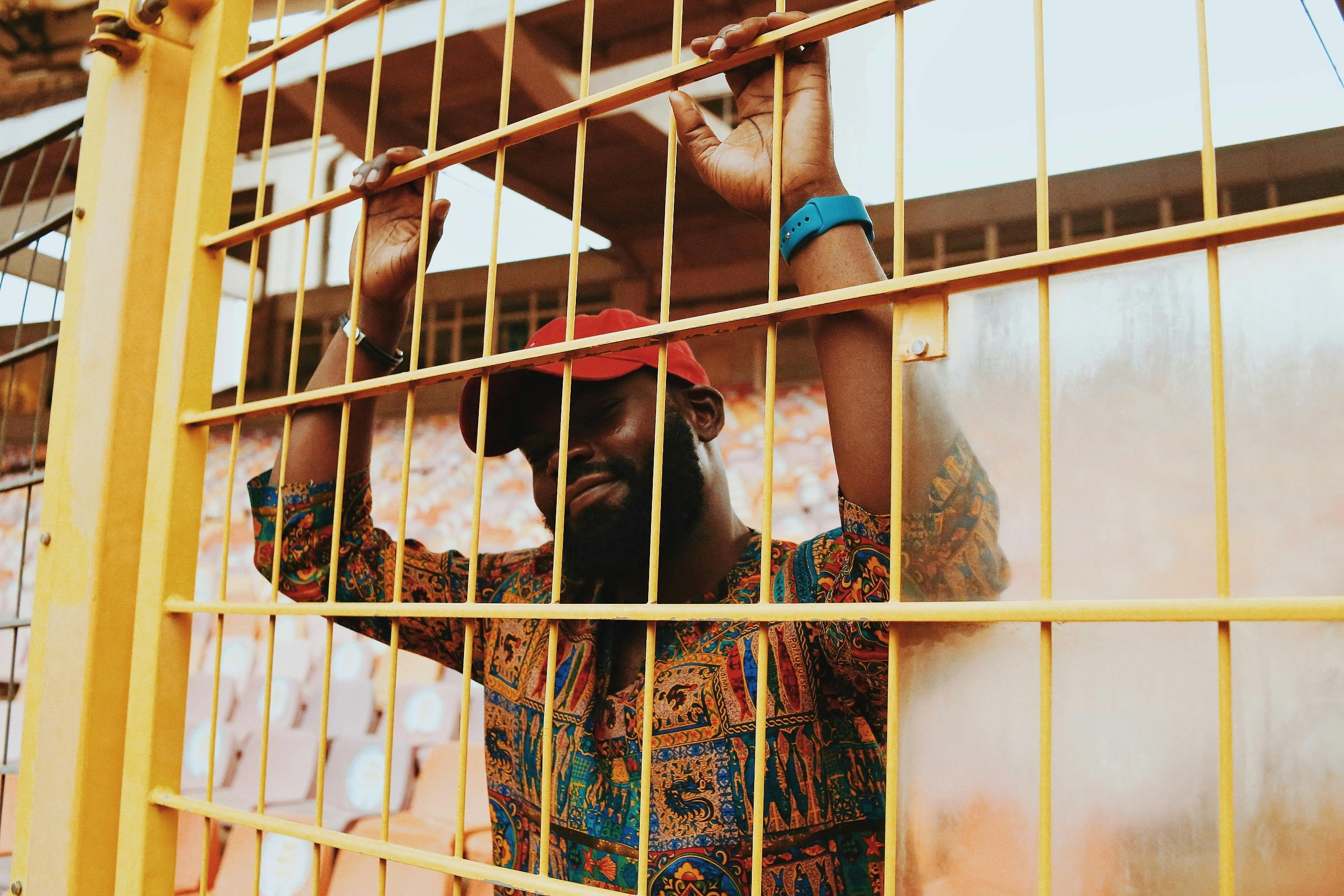 Man behind Fence Bars at Stadium · Free Stock Photo