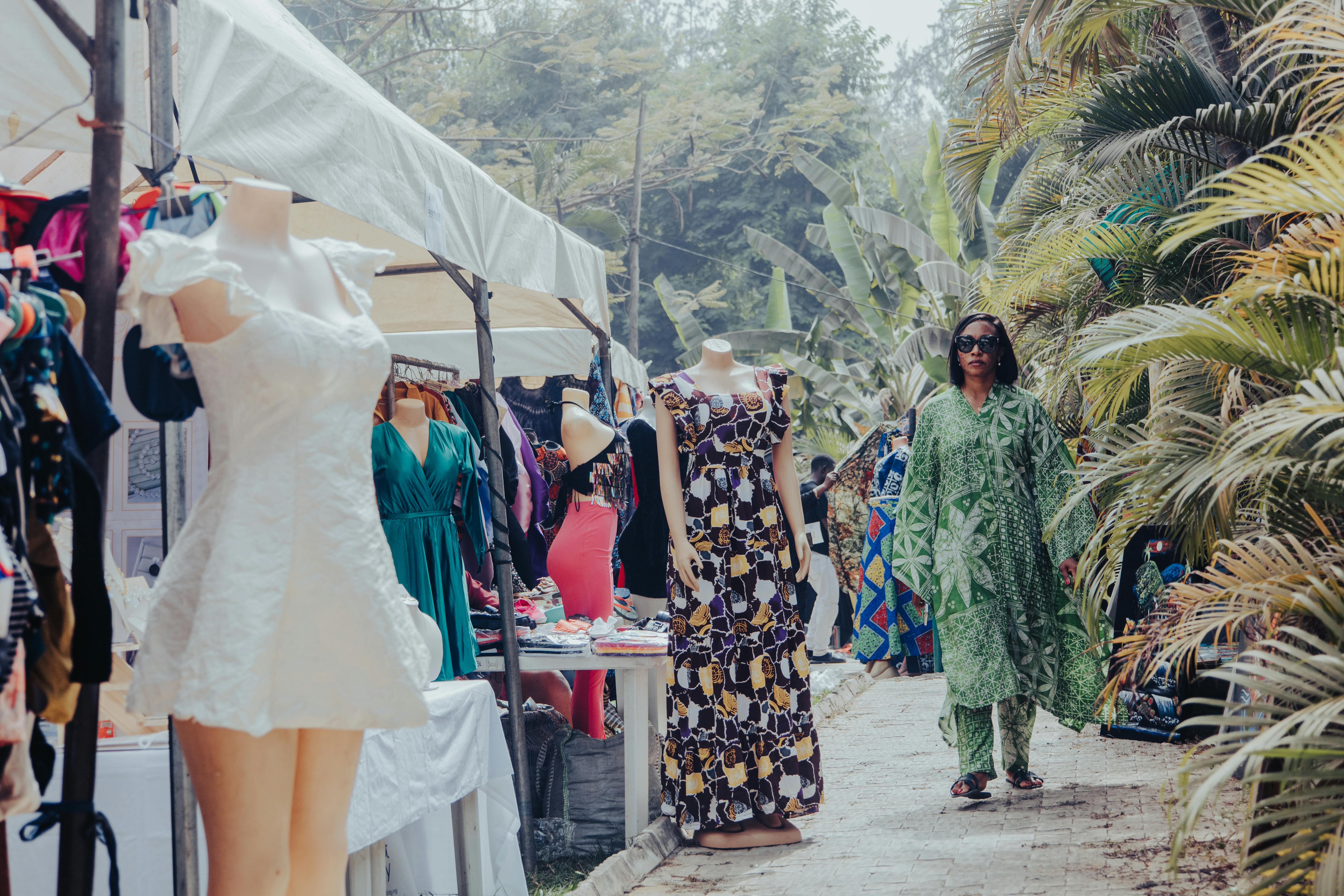 Woman Walking past a Market Stall with Elegant Dresses · Free Stock Photo