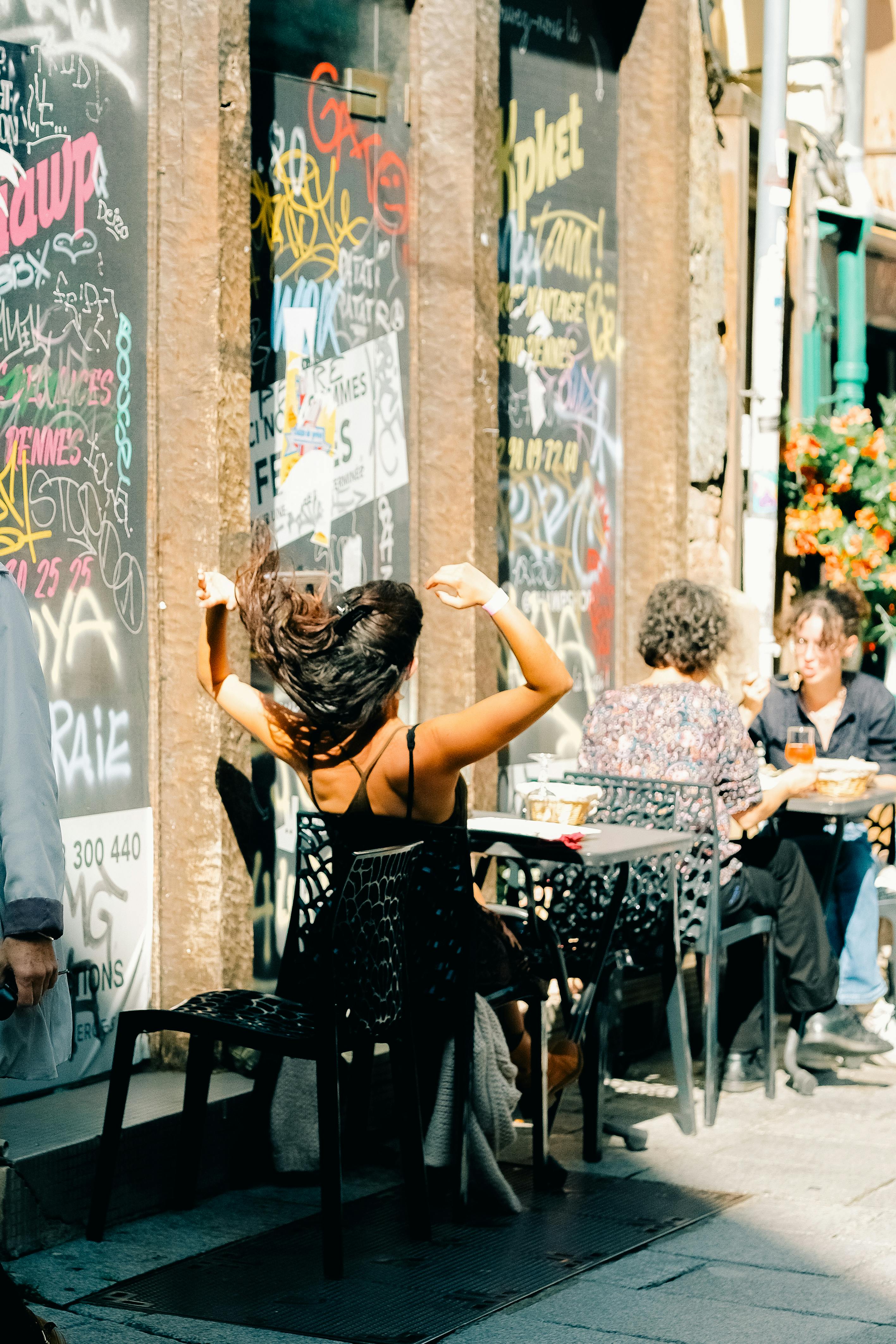 Woman is Tousling Hair at Street Cafe · Free Stock Photo