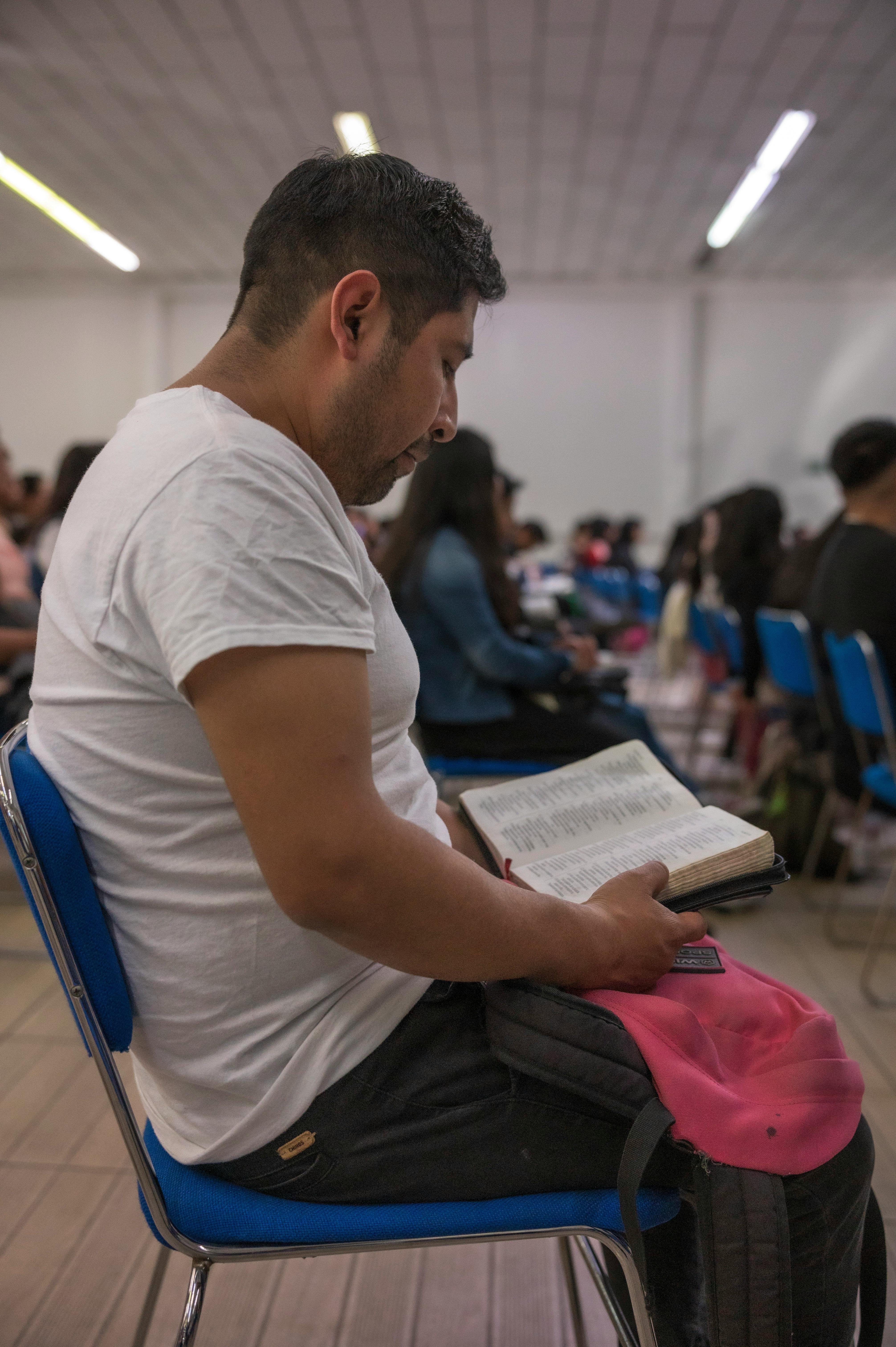 Man Reading a Bible in a Lecture Room · Free Stock Photo