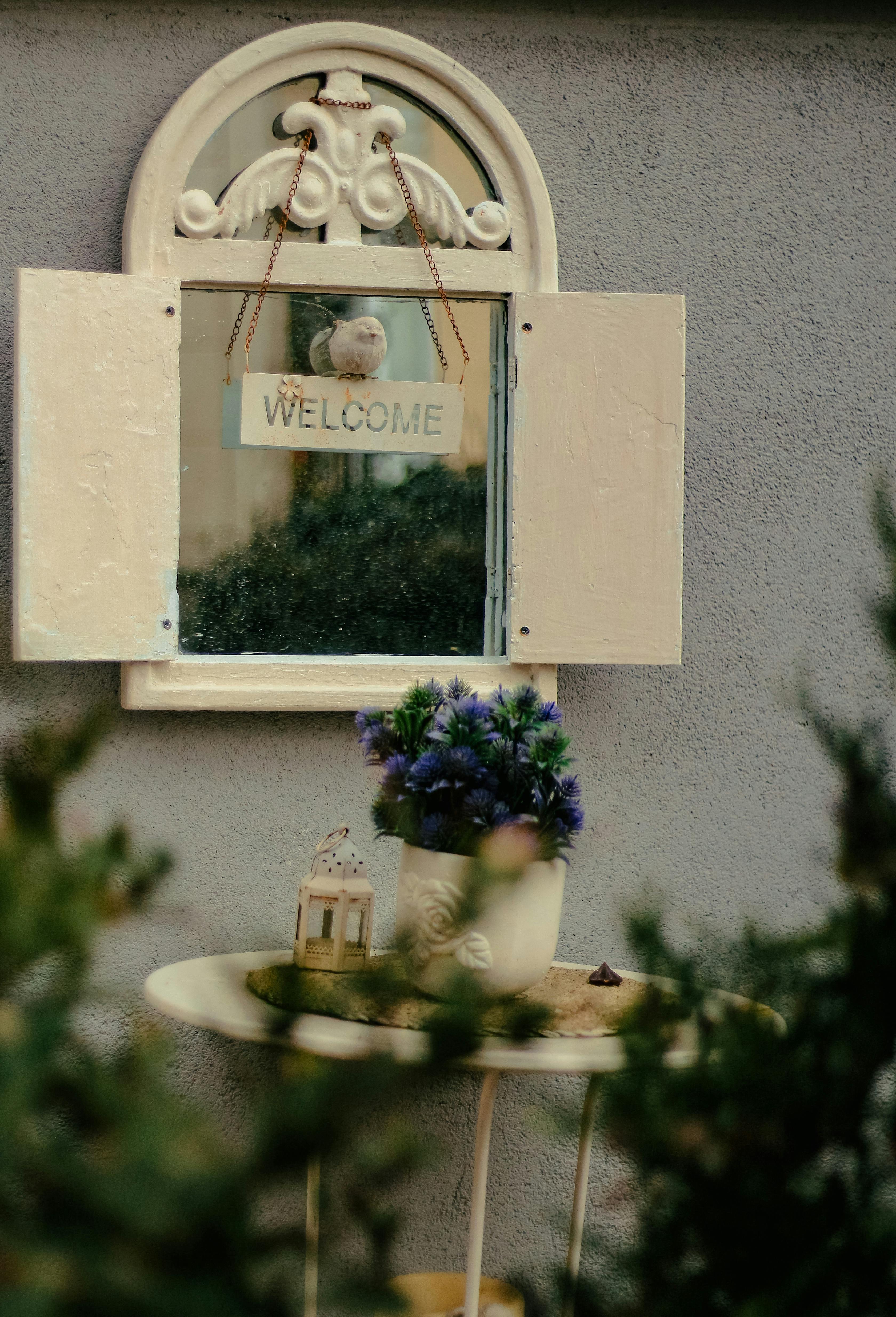 A Potted Plant Standing on a Table by the Window with a Welcome Sign ...