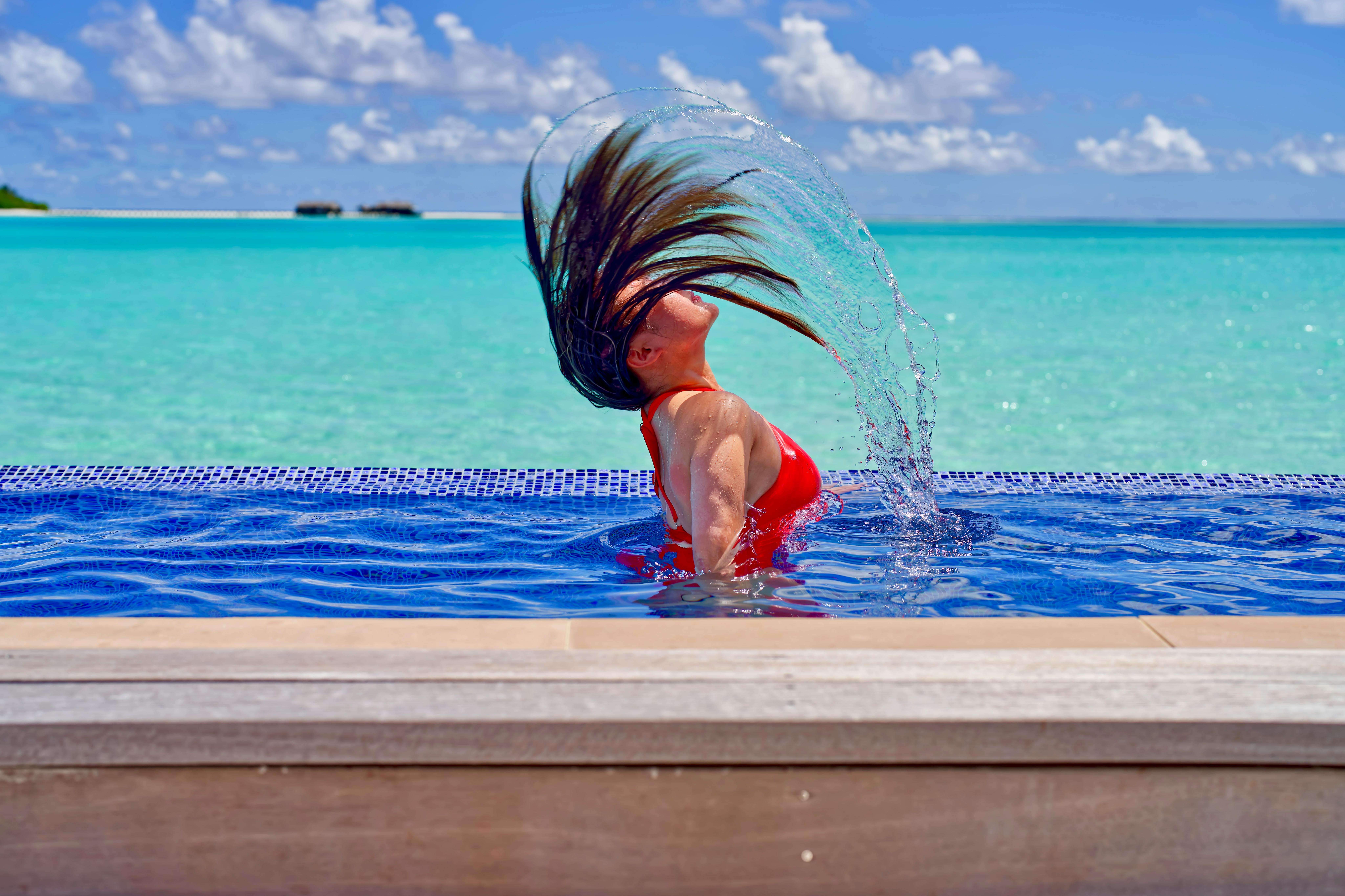 Brunette in Swimming Pool by Sea Tossing Hair · Free Stock Photo