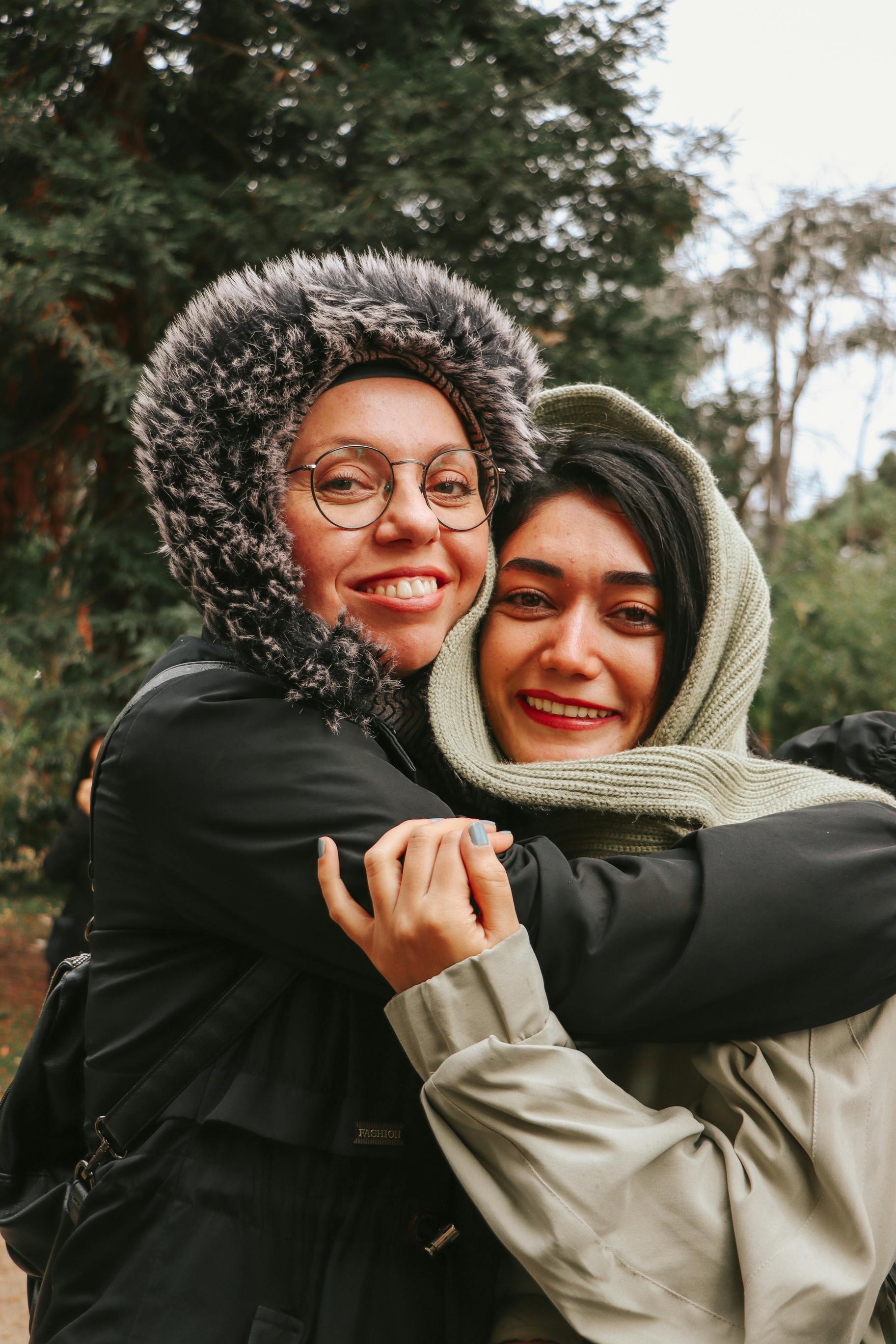 Smiling Embracing Women in Jackets · Free Stock Photo