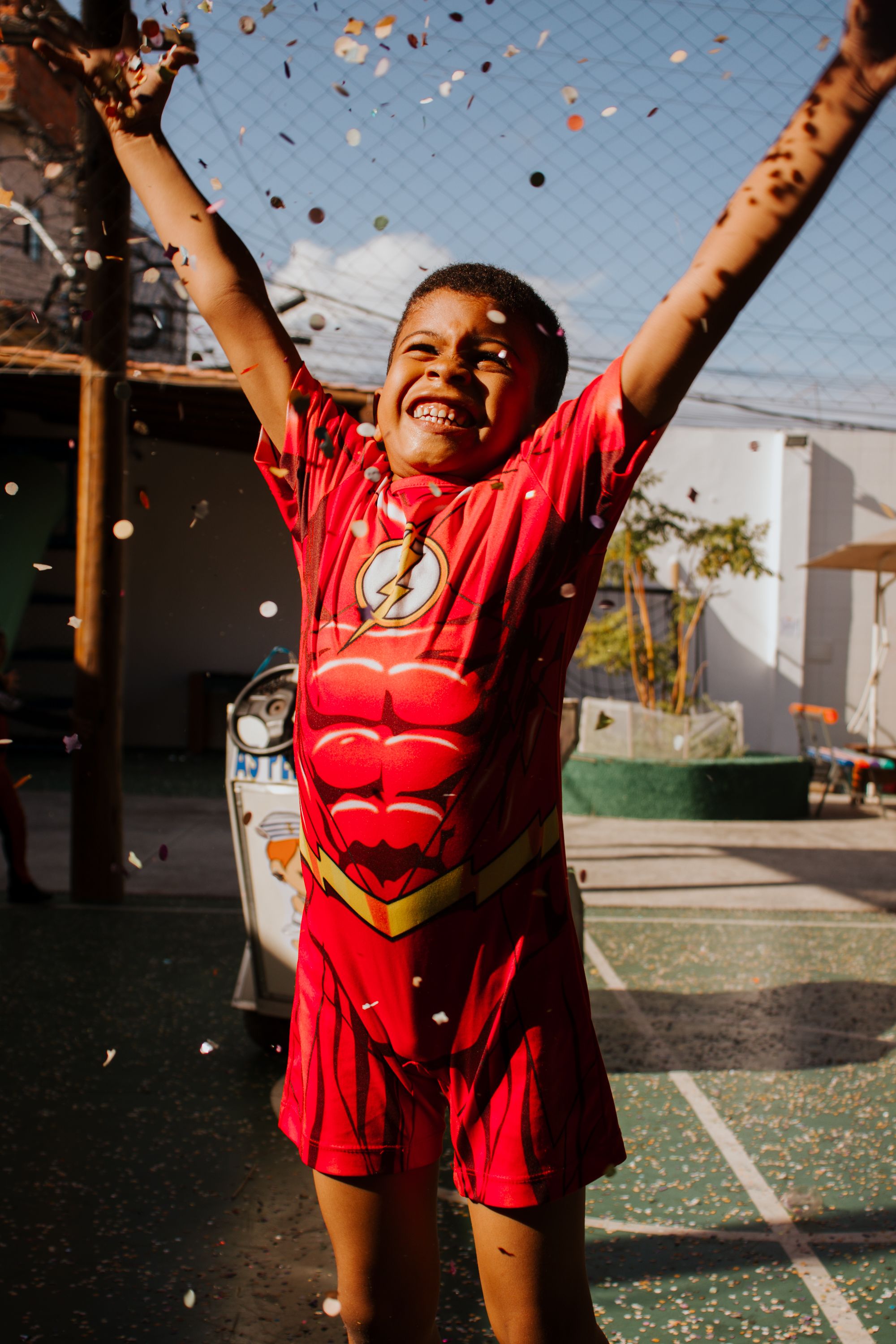 Boy in Flash Costume Standing with Arms Raised · Free Stock Photo