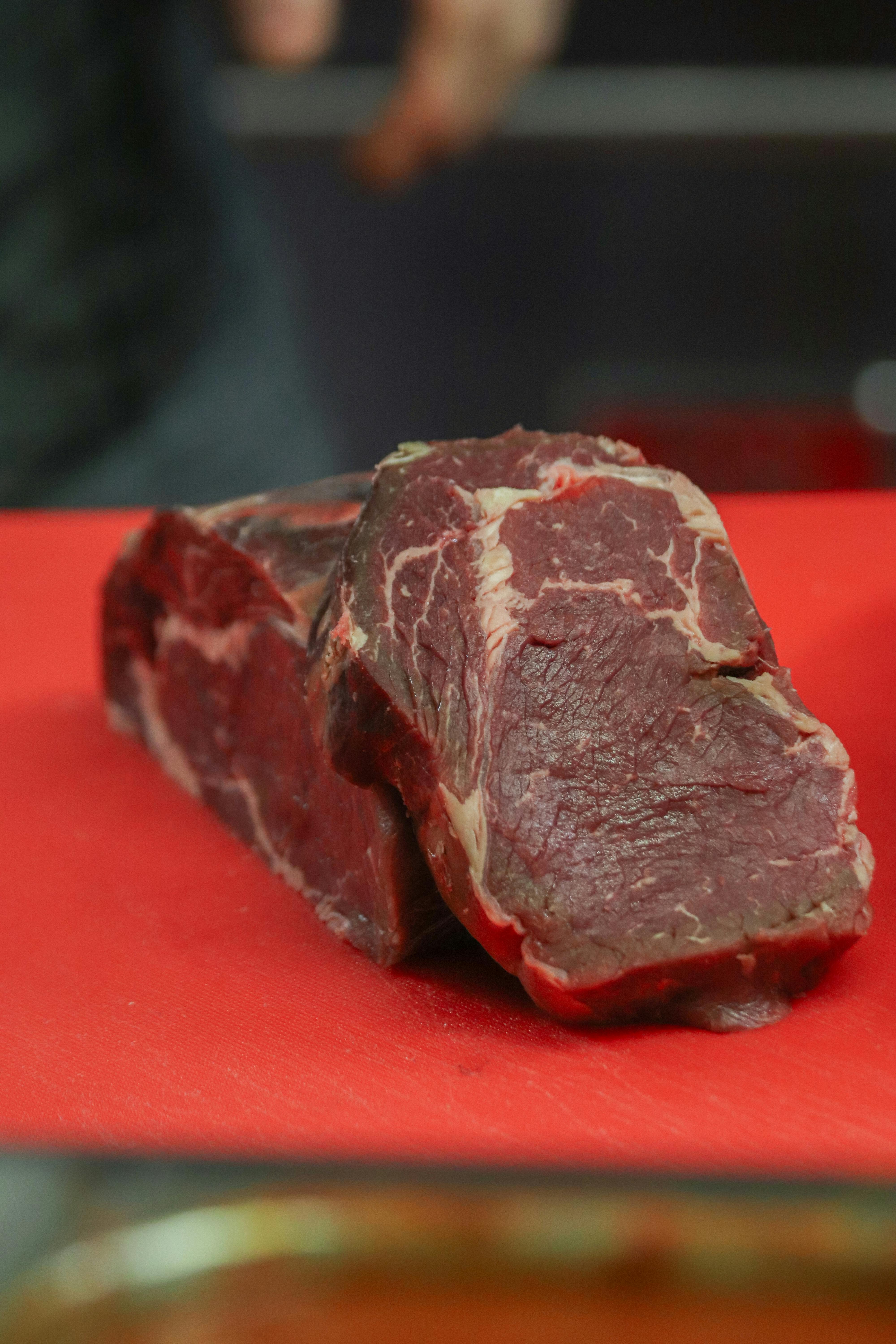 A piece of meat on a red cutting board · Free Stock Photo