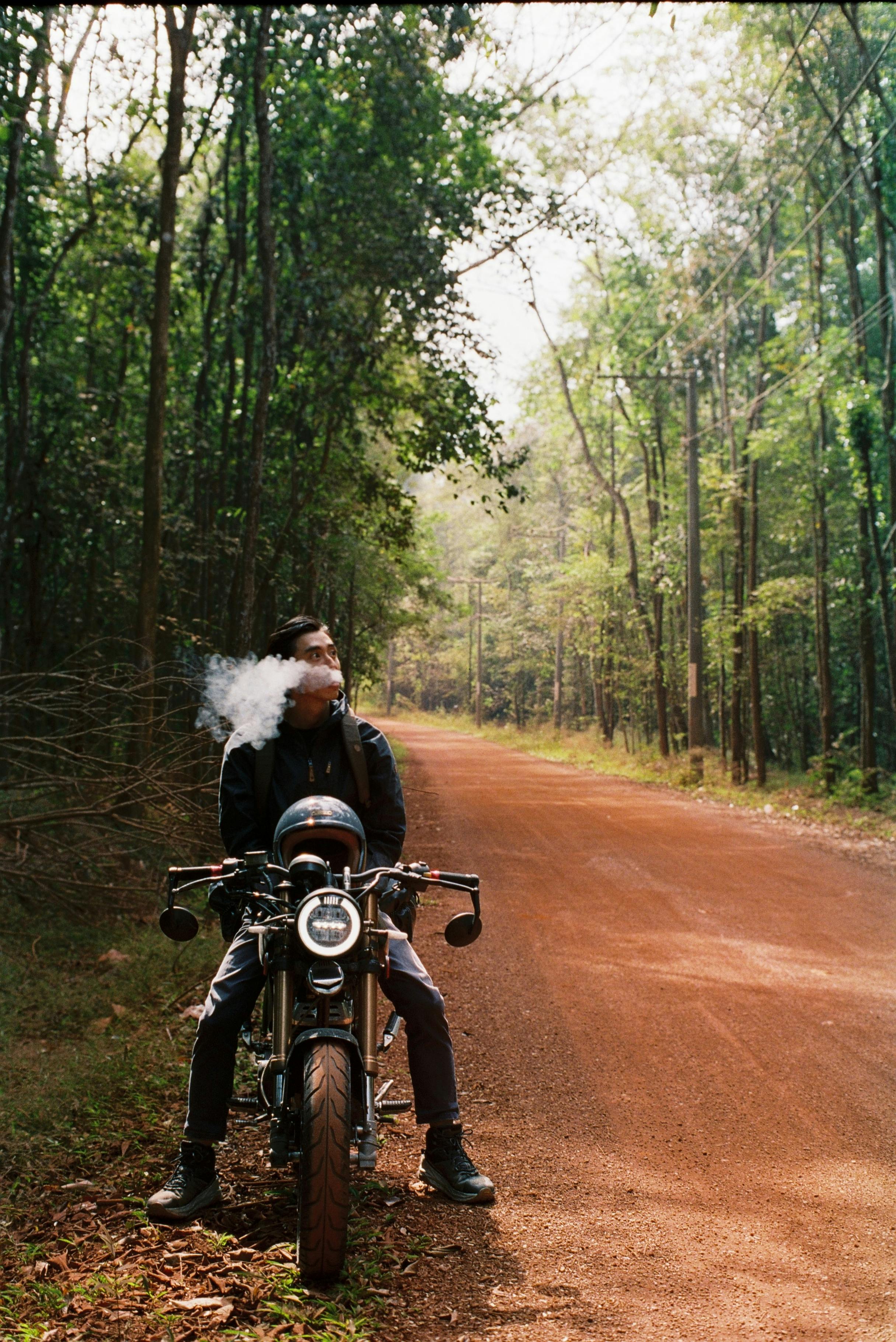 Smoking Biker Sits in Motorcycle on Side of Rural Road · Free Stock Photo