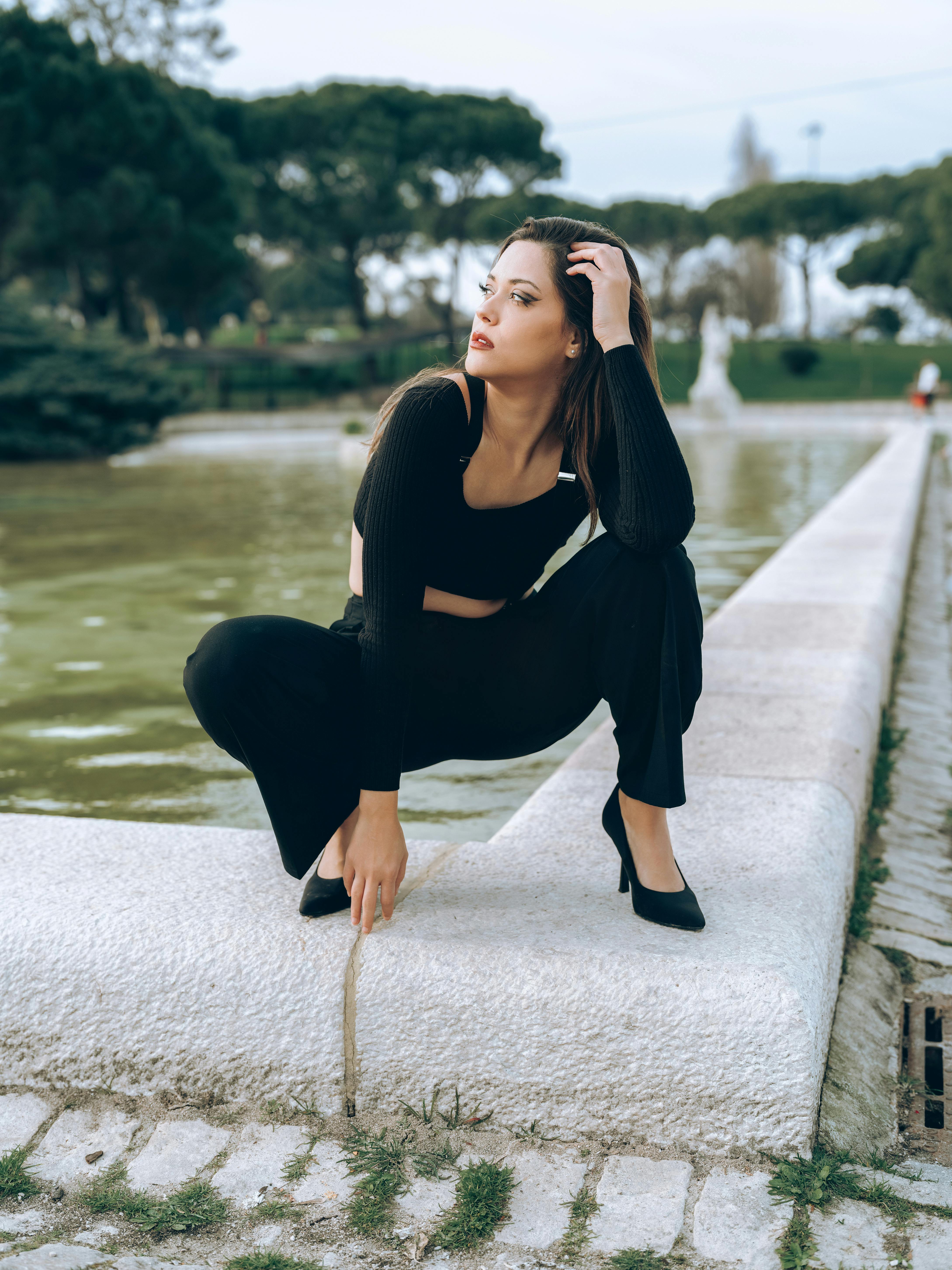 Young Woman Crouching on the Corner of a Fountain in a Fashionable ...