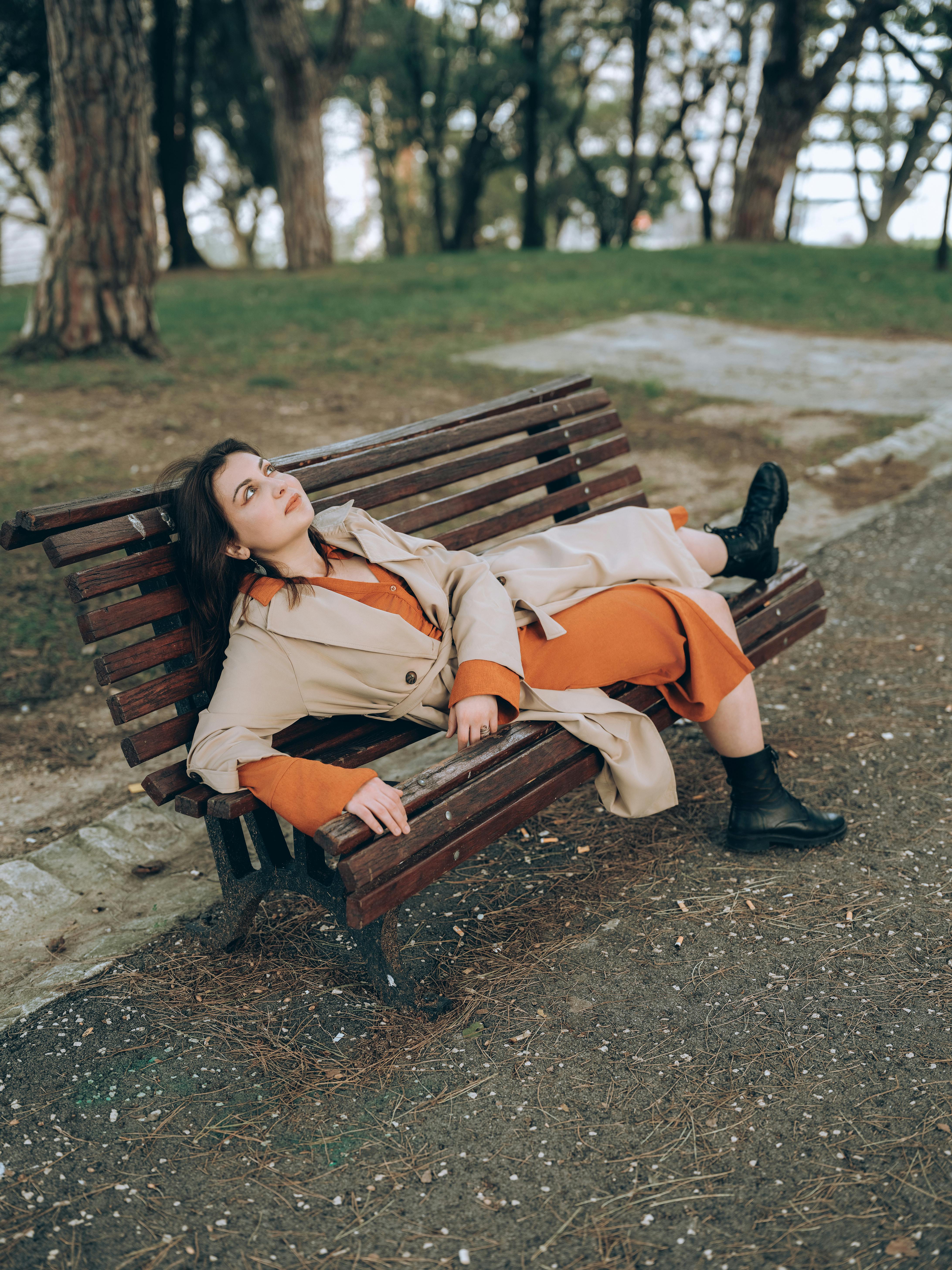 Woman in Trench Lying Down on Bench at Park · Free Stock Photo