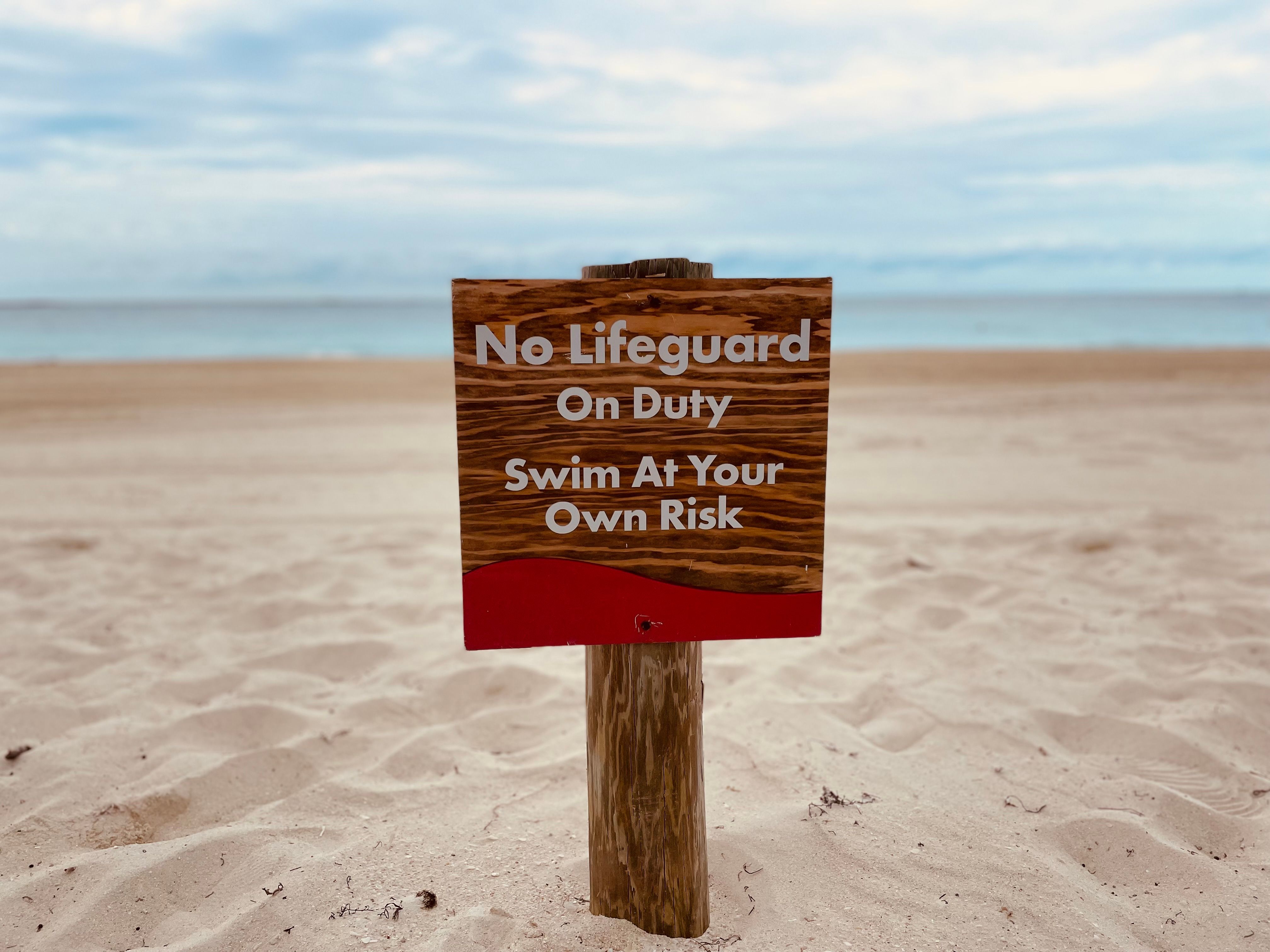 Sign on the Beach Warning About the Lack of a Lifeguard · Free Stock Photo