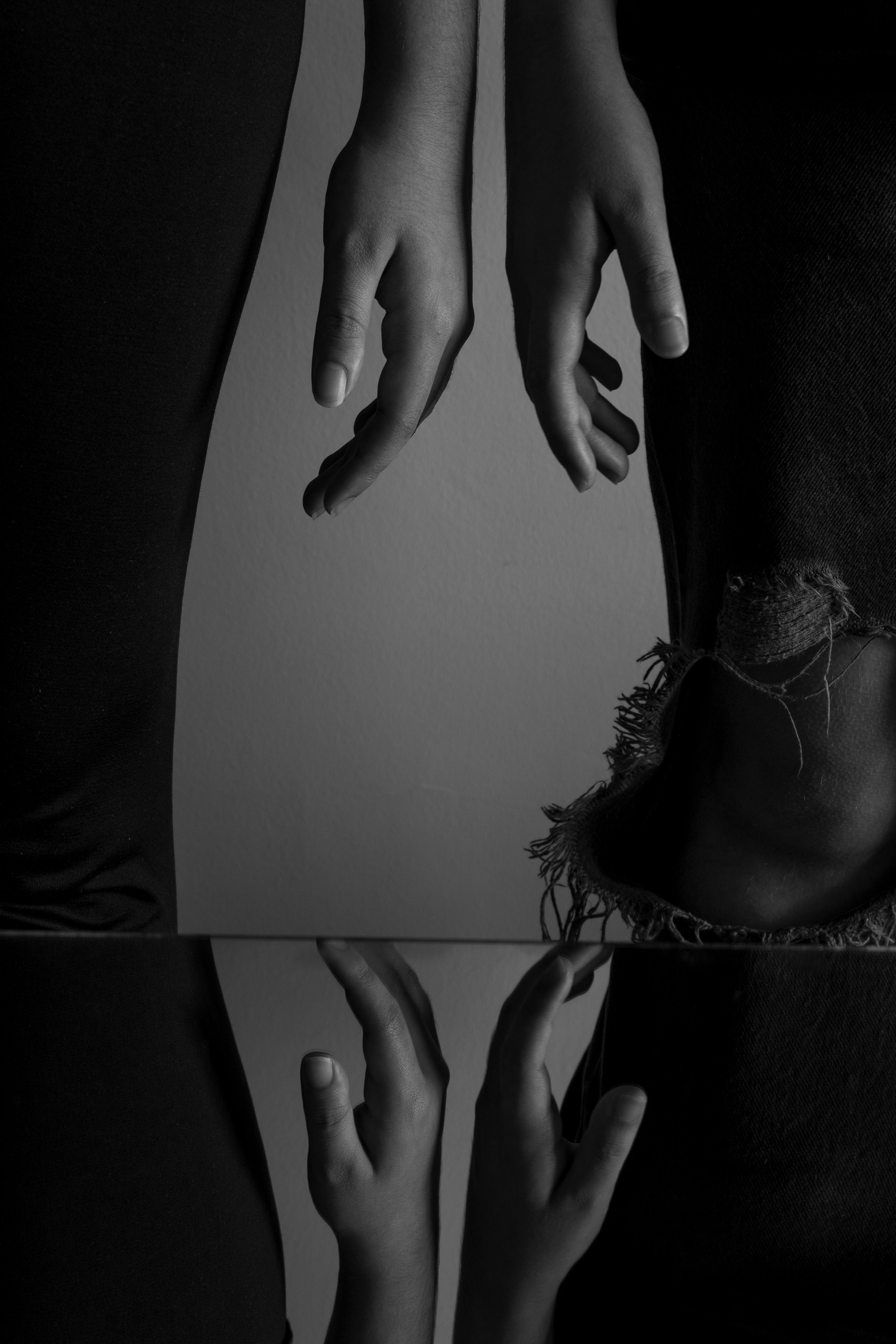 Black and White Photo of Hands and Legs of Two People Reflecting in a ...