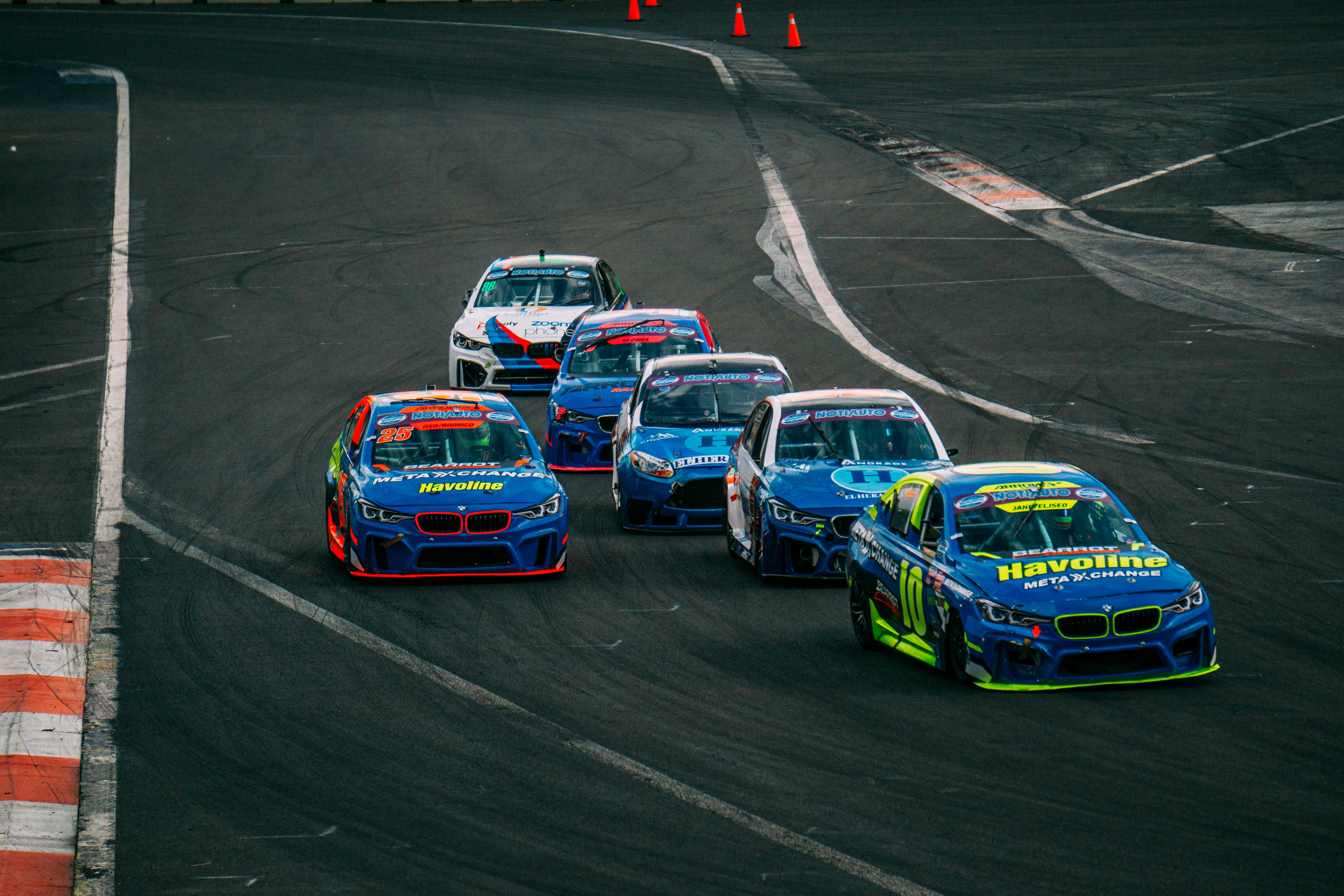 A group of cars driving on a race track · Free Stock Photo