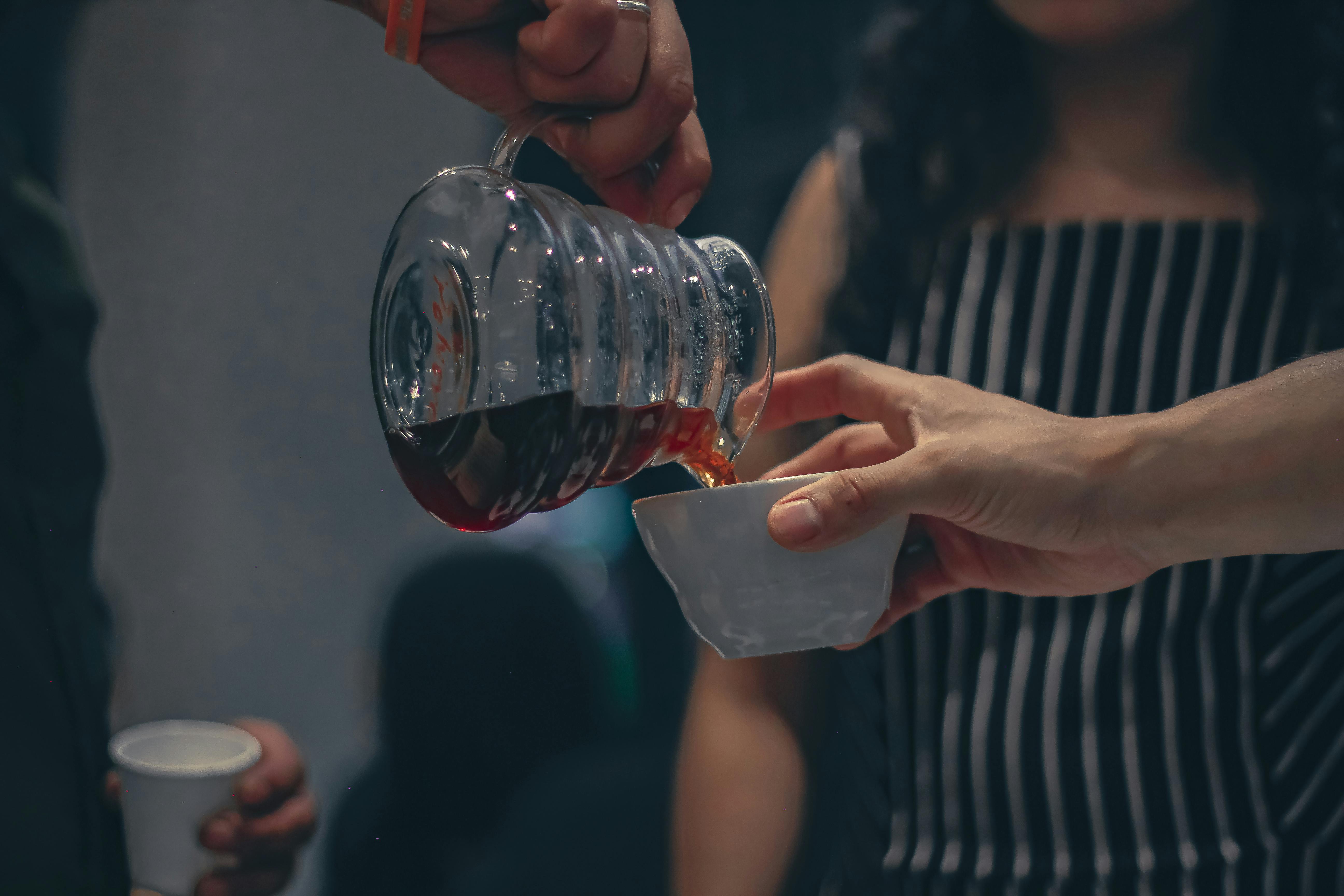 Cheerful ethnic coworkers with teapot at table · Free Stock Photo
