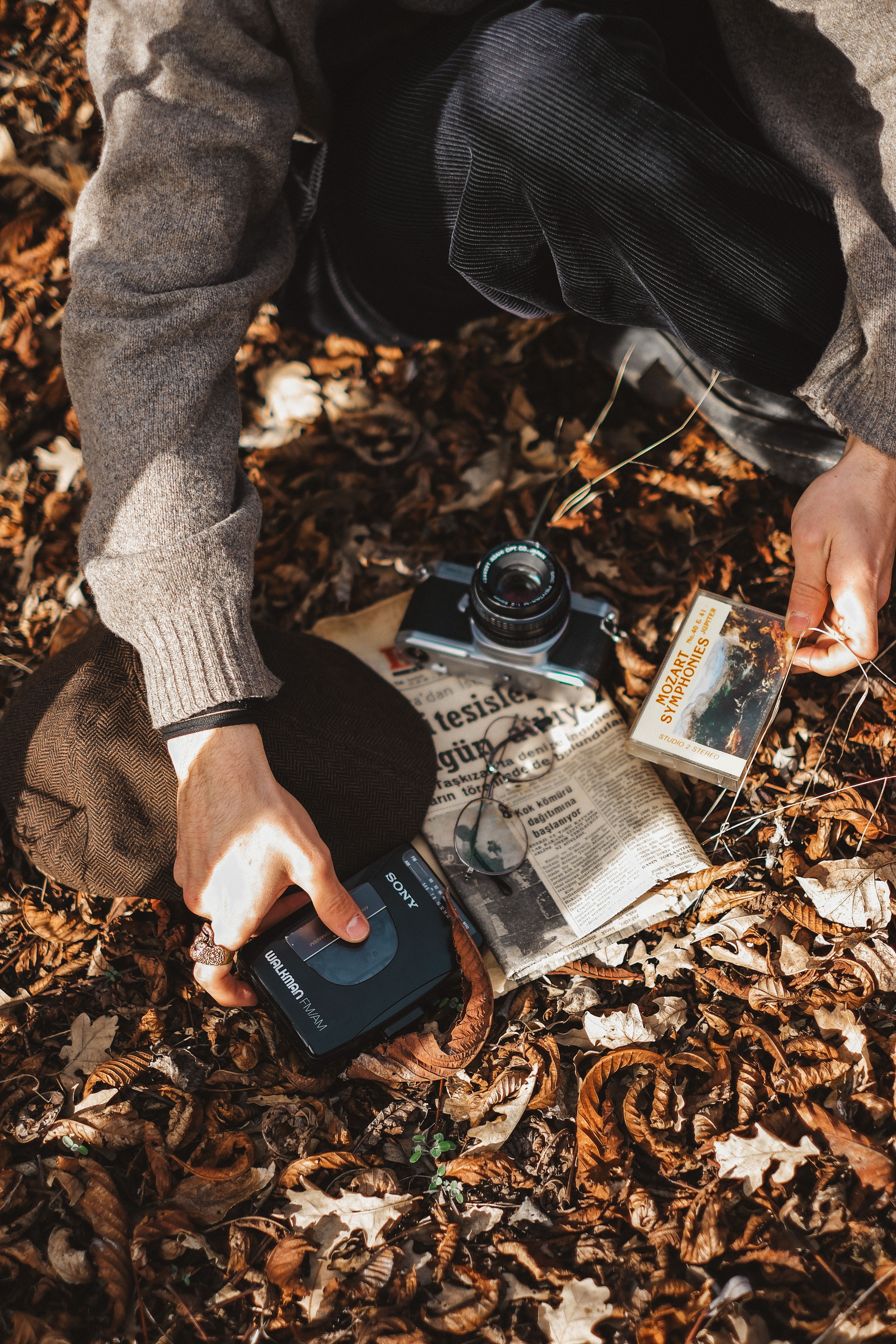 Man Squatting over Camera and Newspaper on Ground in Autumn · Free ...