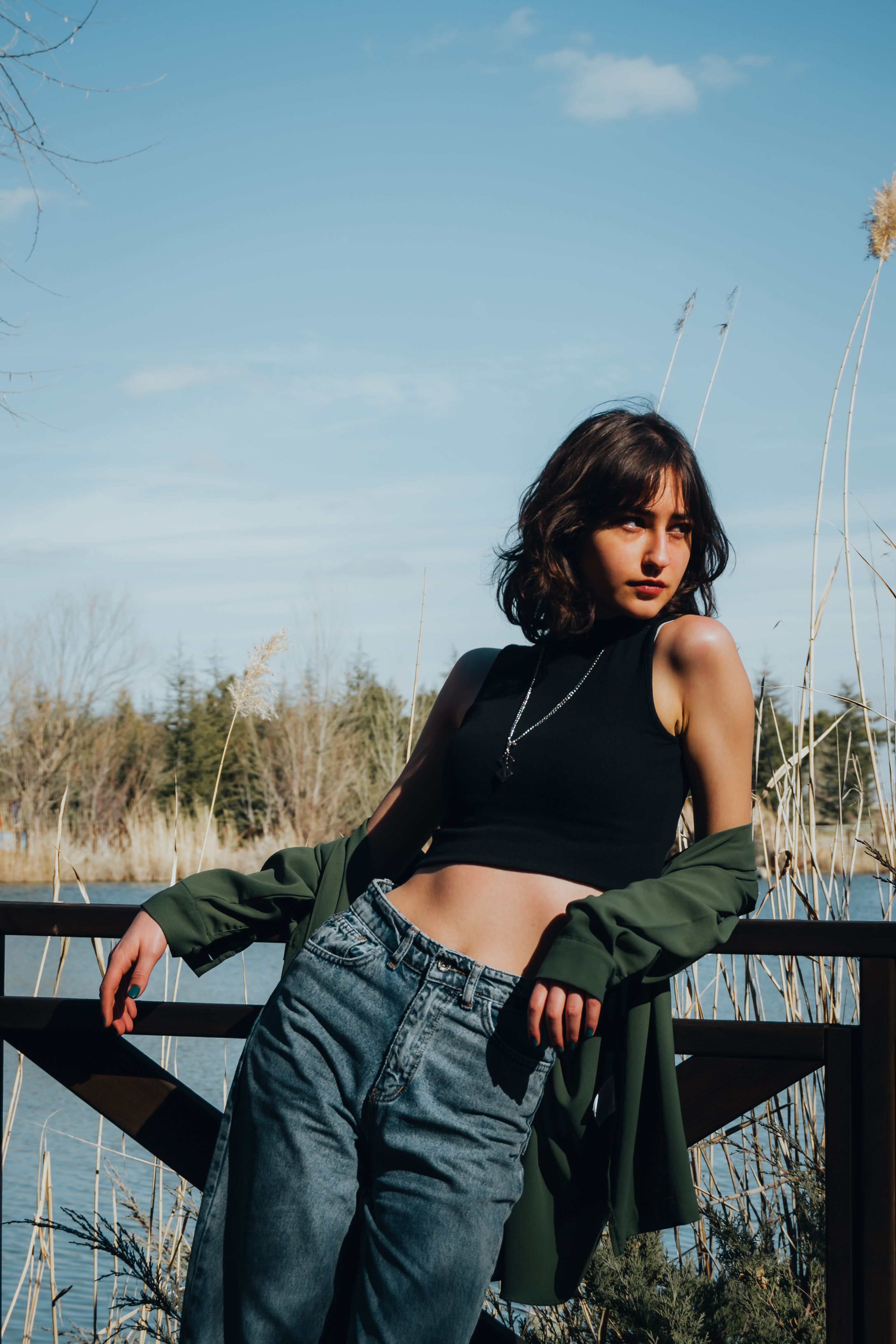 Young Woman in a Tank Top and Jeans Standing near a Body of Water ...
