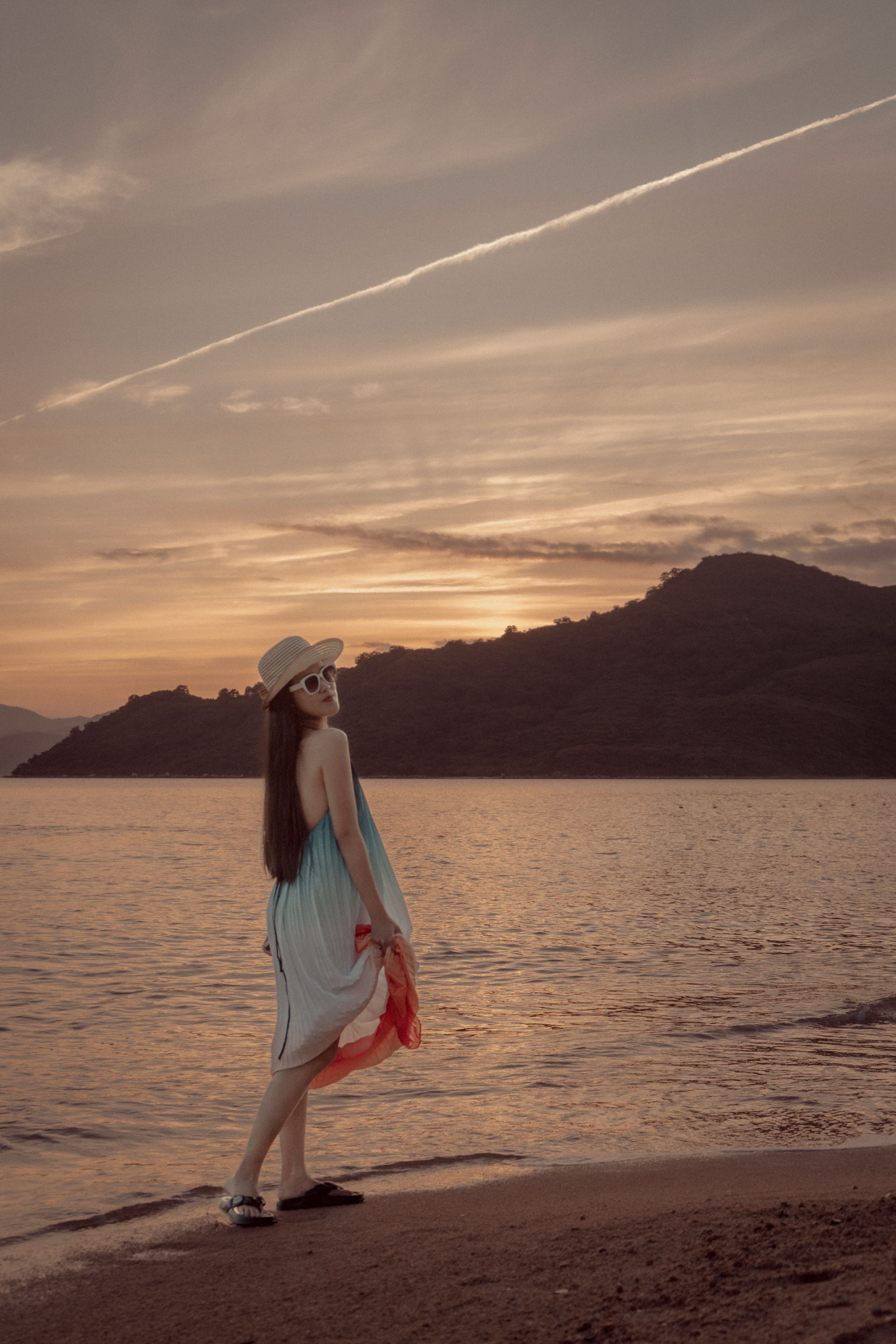 Woman in Hat and Sundress Posing on Beach at Sunset · Free Stock Photo