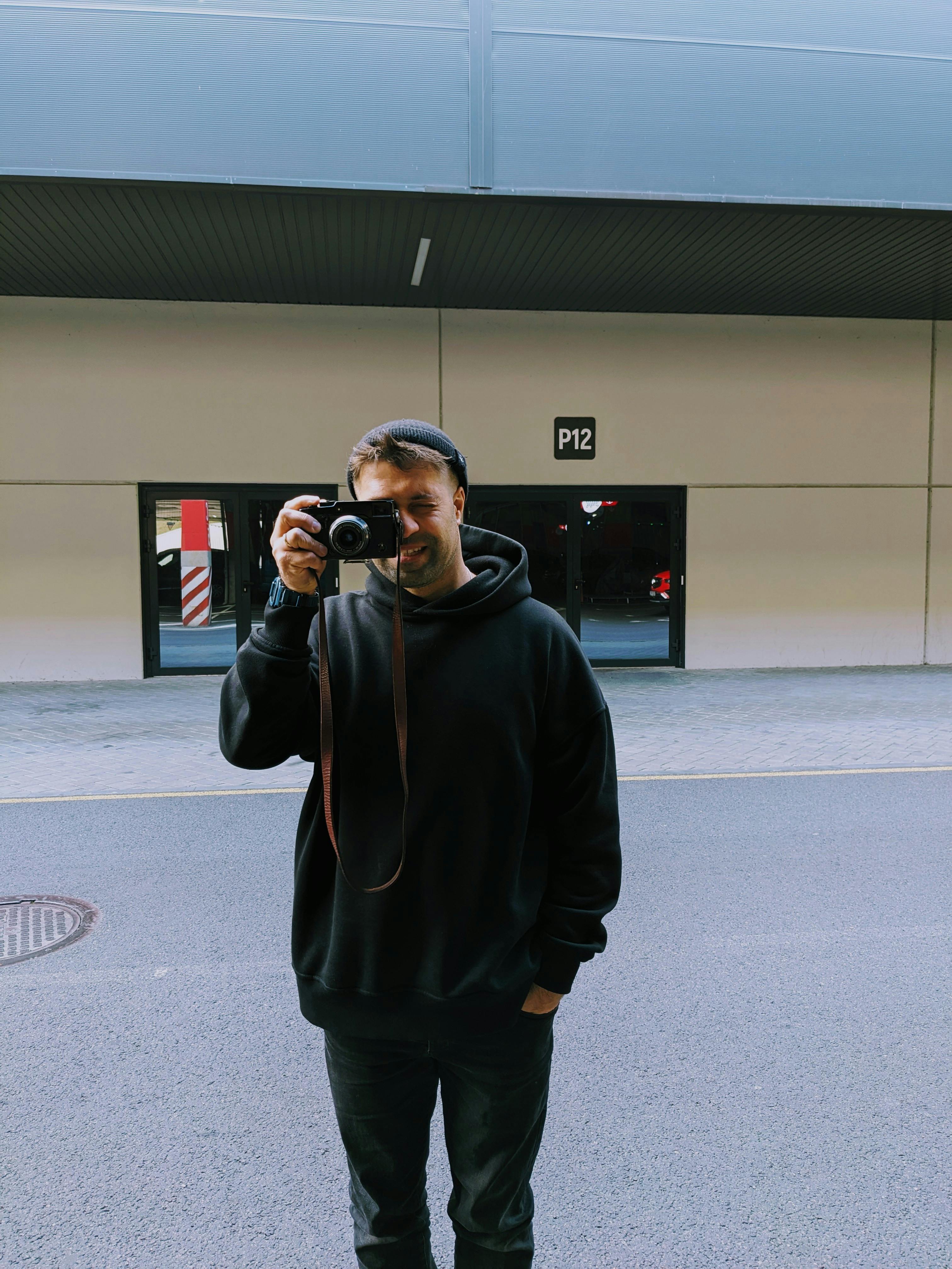 Man in Hoodie Holding Camera · Free Stock Photo