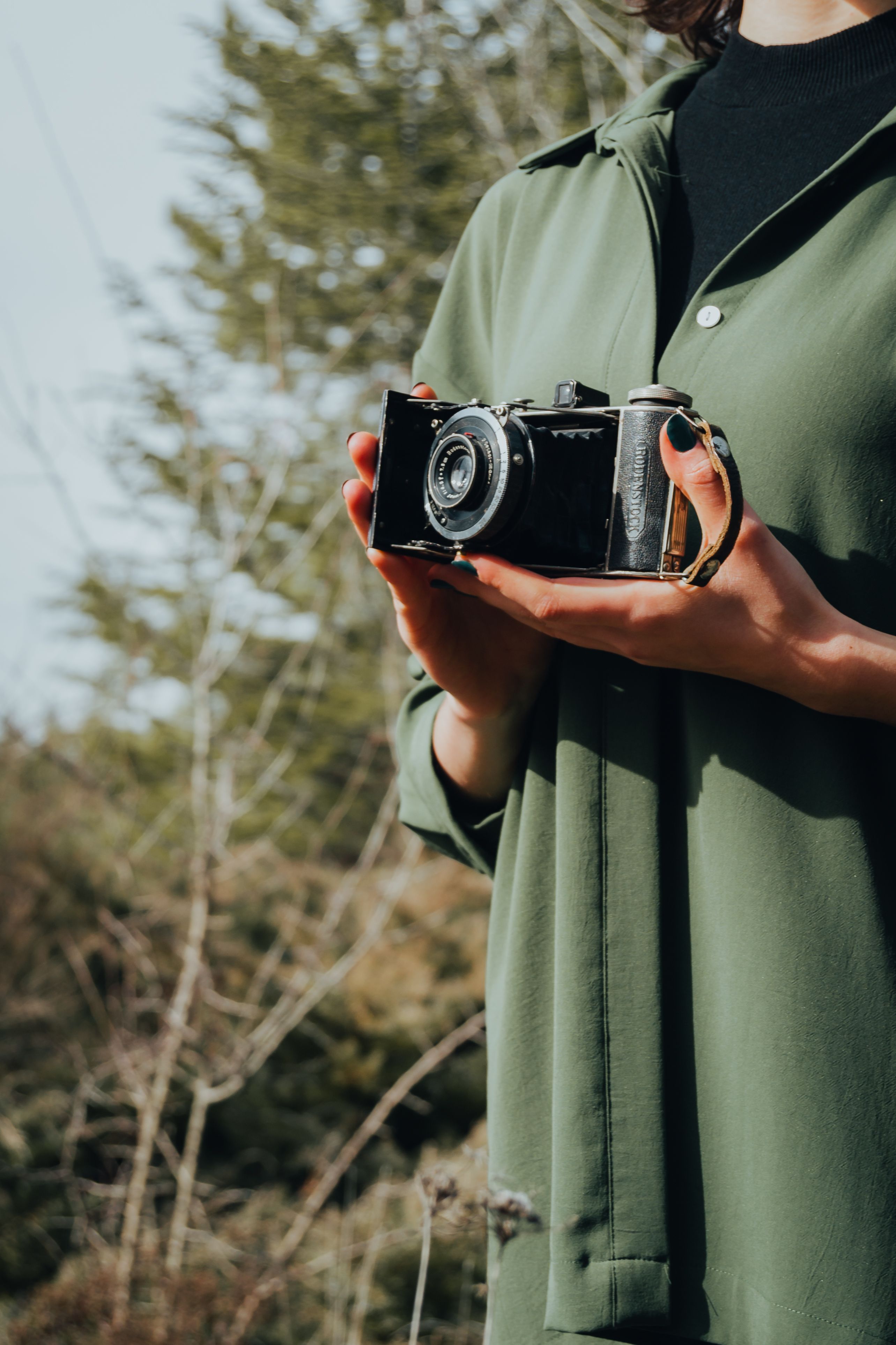 Woman in Green Clothes Holding Camera · Free Stock Photo