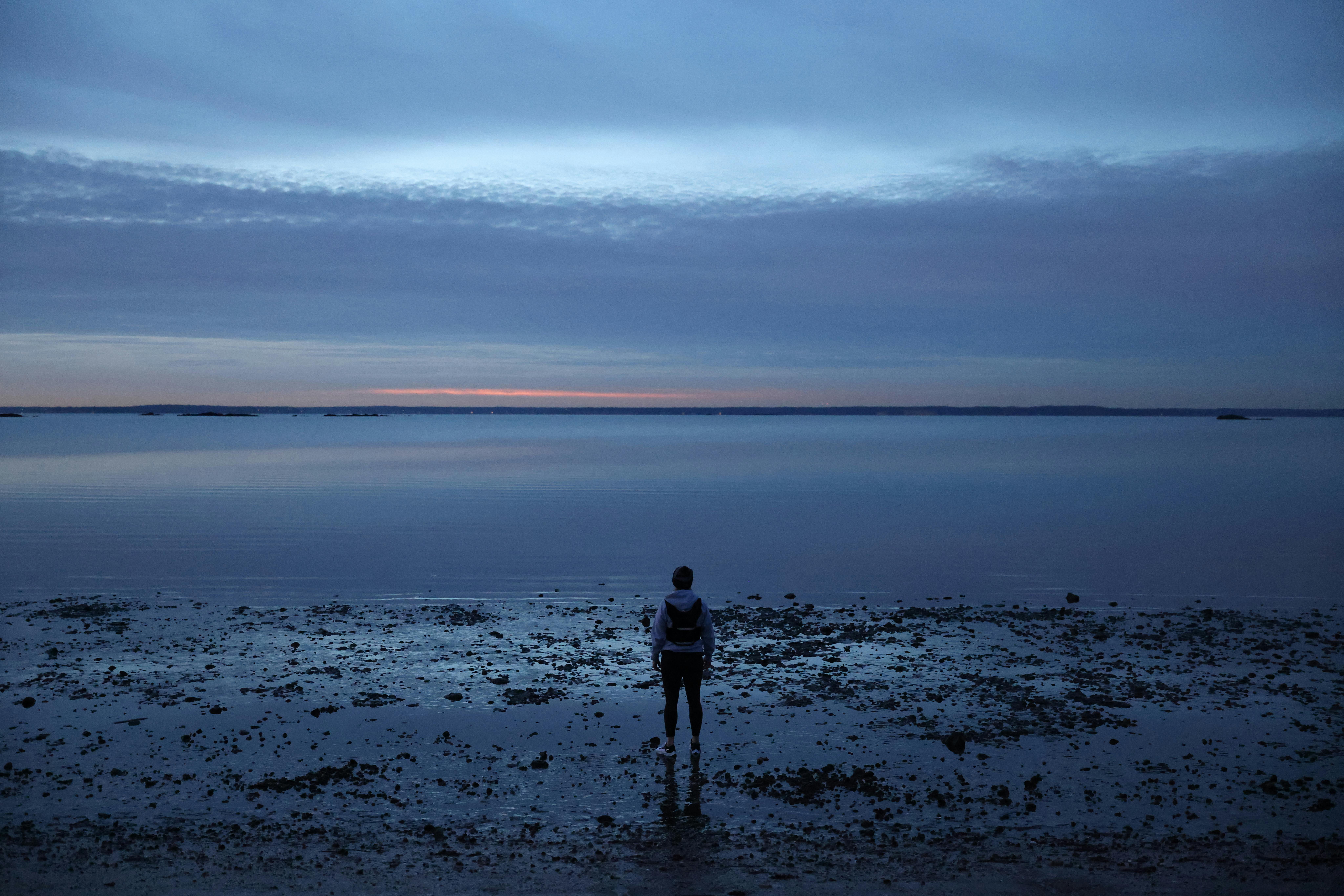 Man Standing on Beach Looking into the Sea on Evening · Free Stock Photo