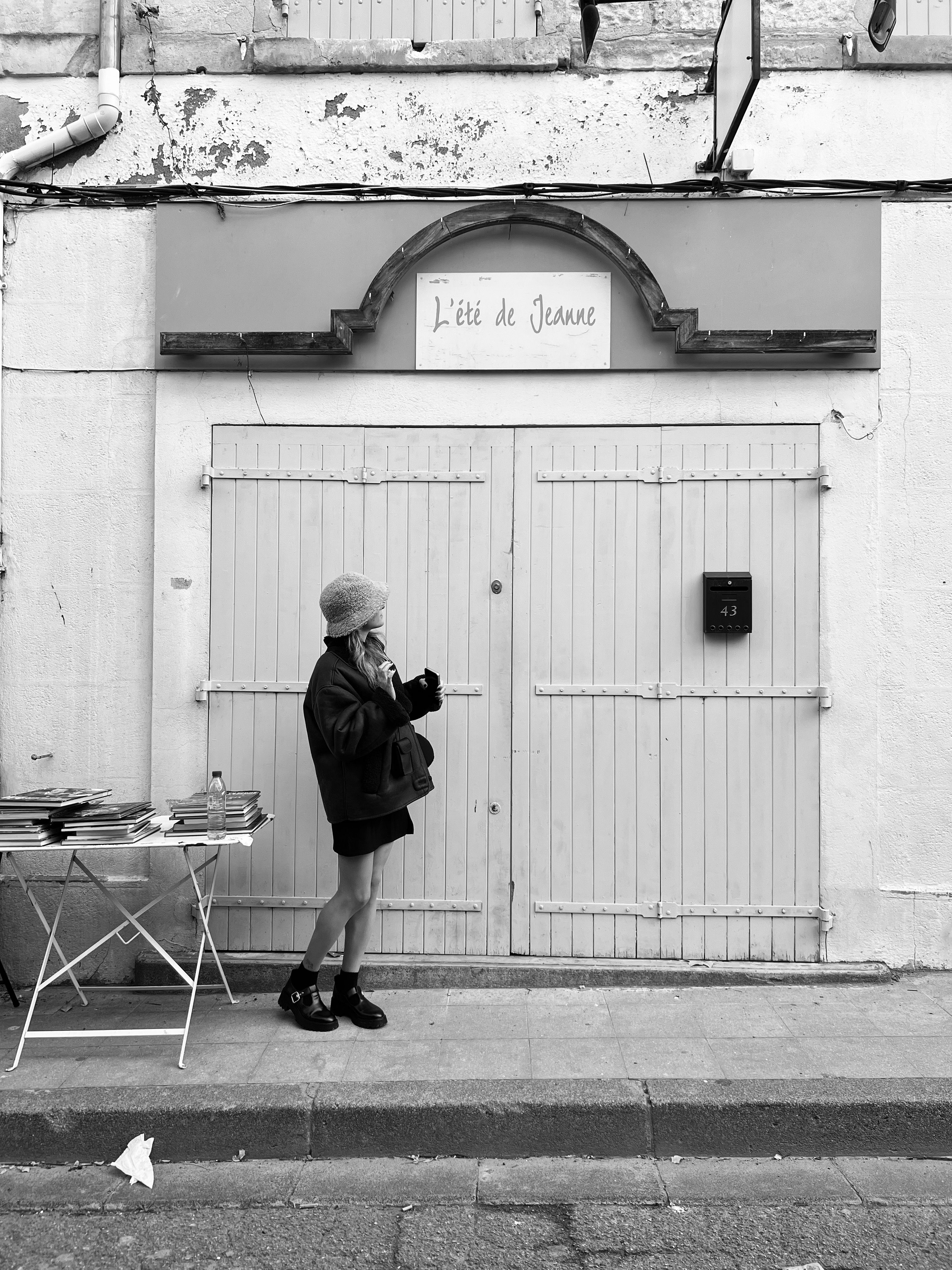 Woman in Hat and Jacket Standing near Gate on Sidewalk · Free Stock Photo
