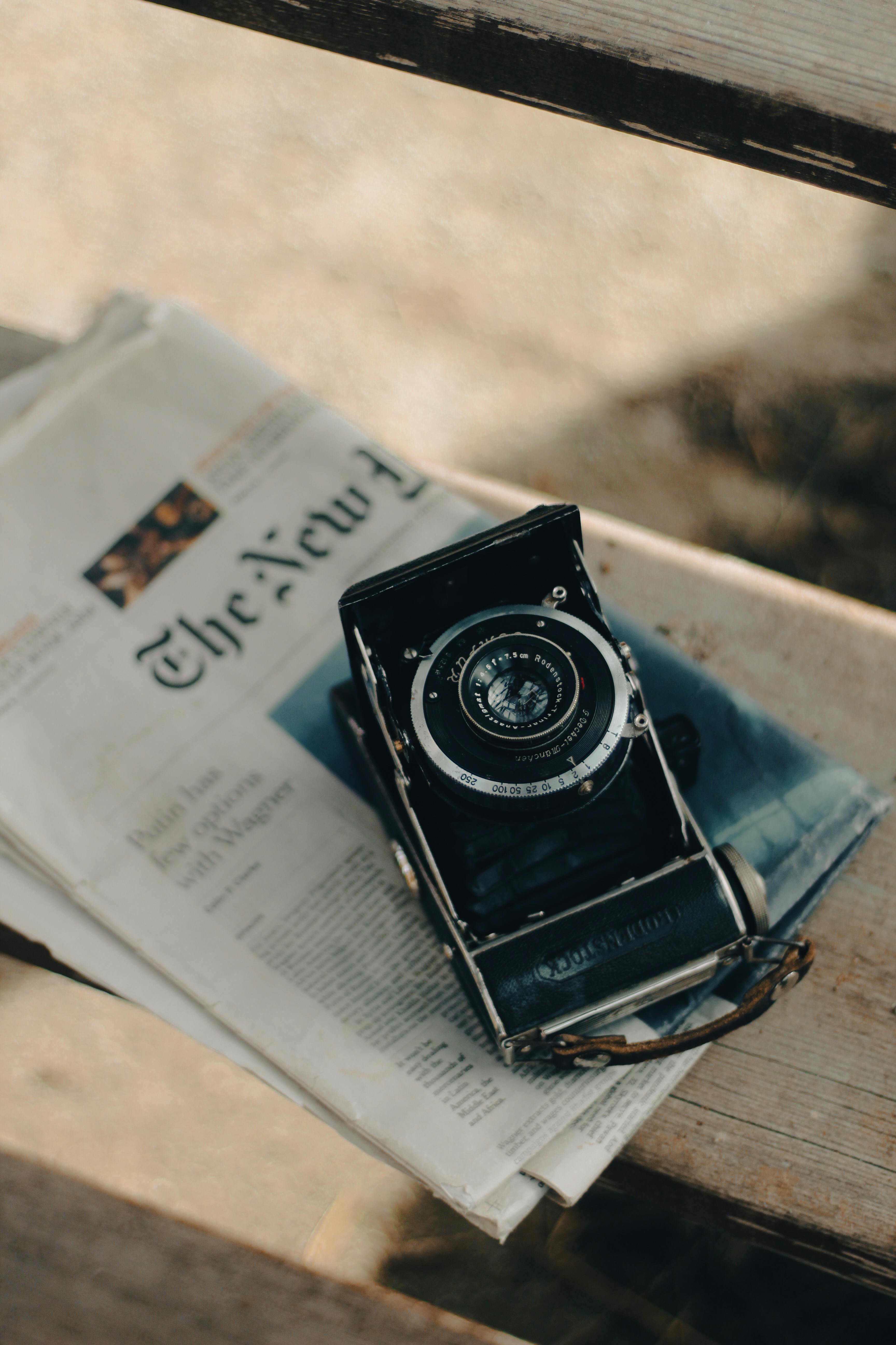 An old camera sitting on top of a newspaper · Free Stock Photo