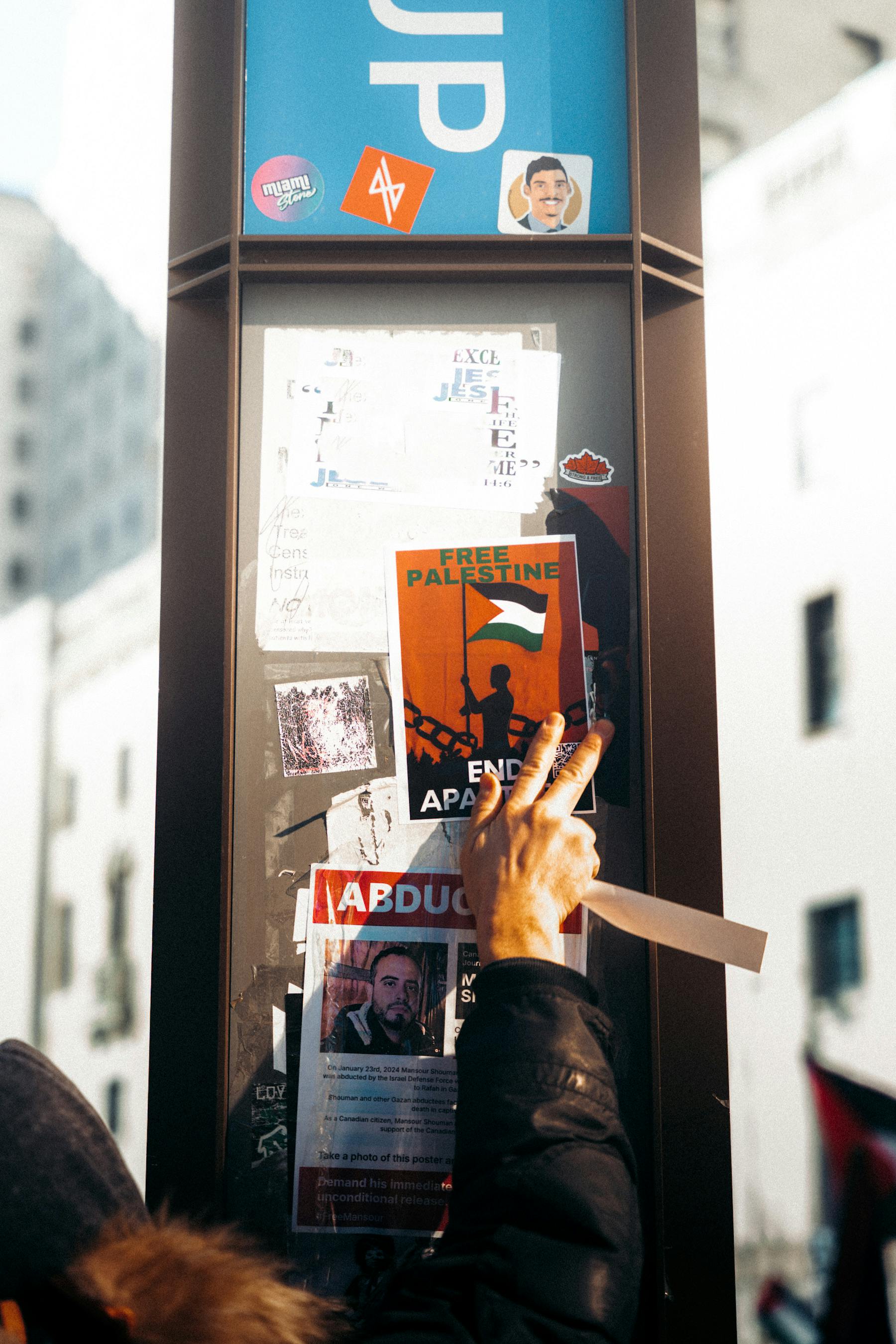 Person Placing Sticker on Pole · Free Stock Photo