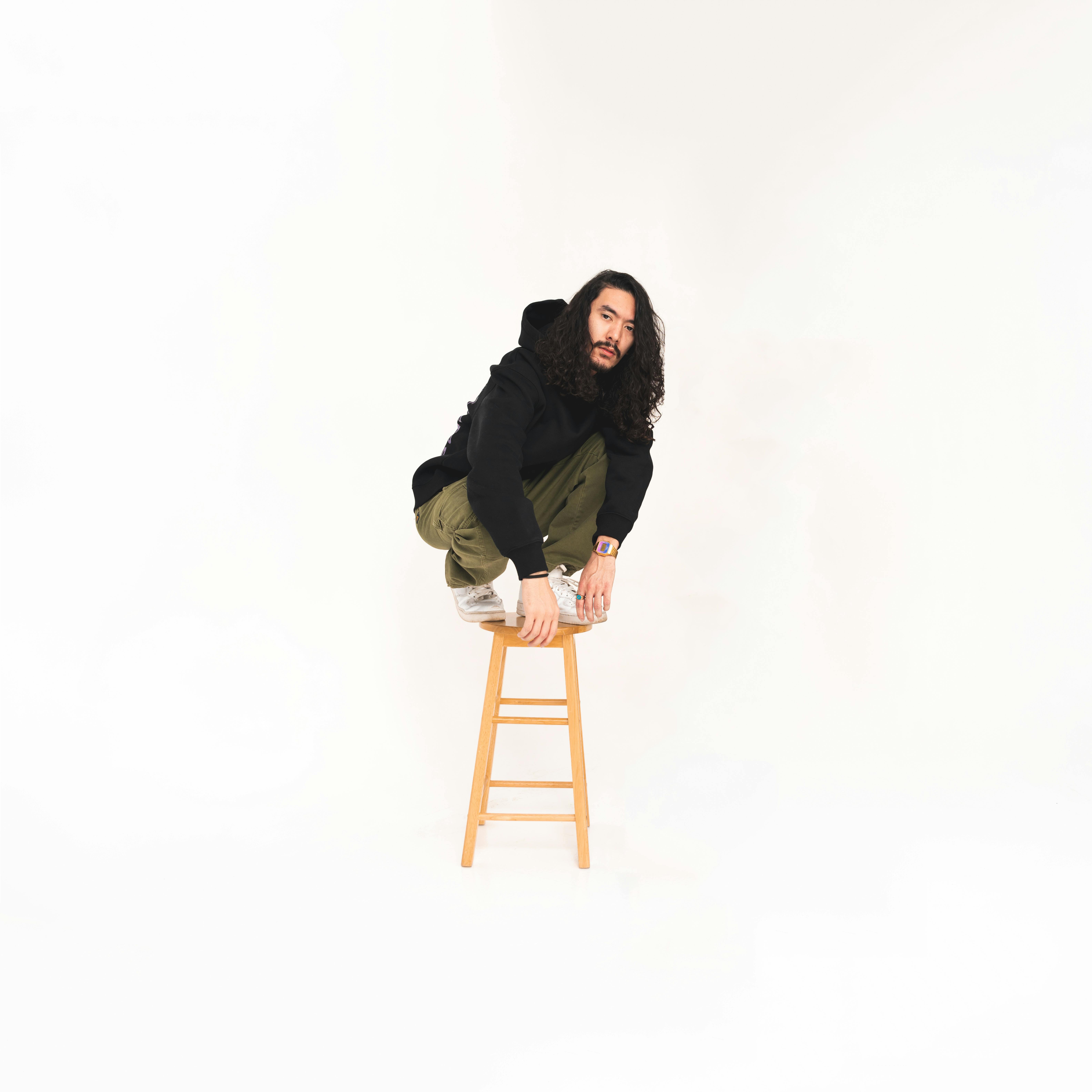 Model in Hoodie Crouching on Stool · Free Stock Photo