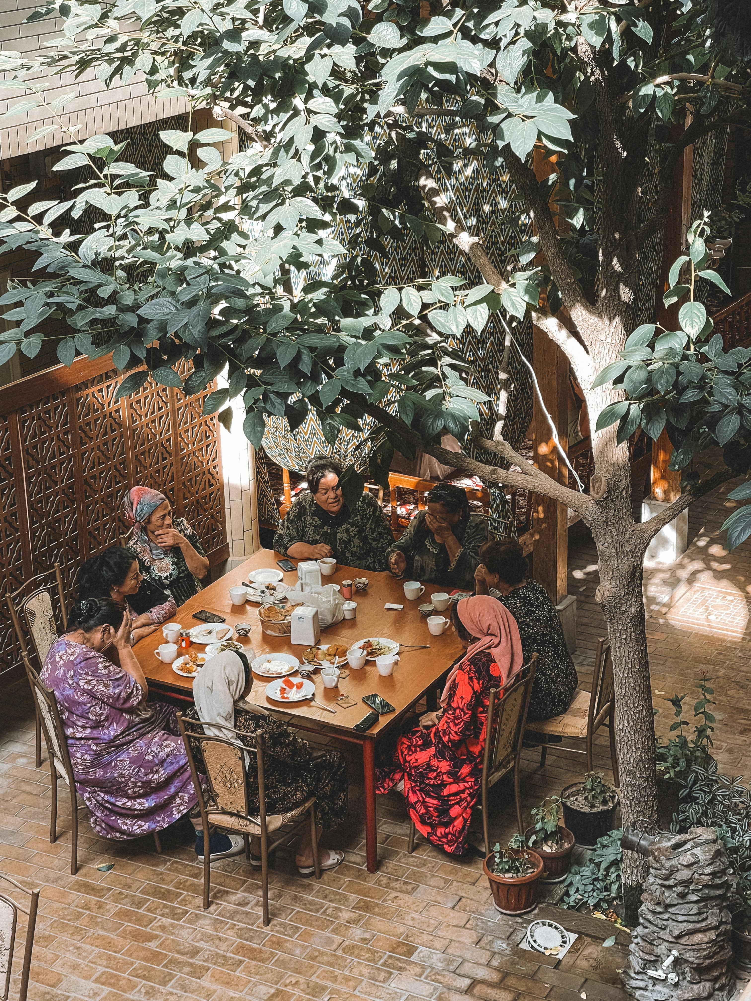 Women Sitting around Table on Patio under Tree · Free Stock Photo