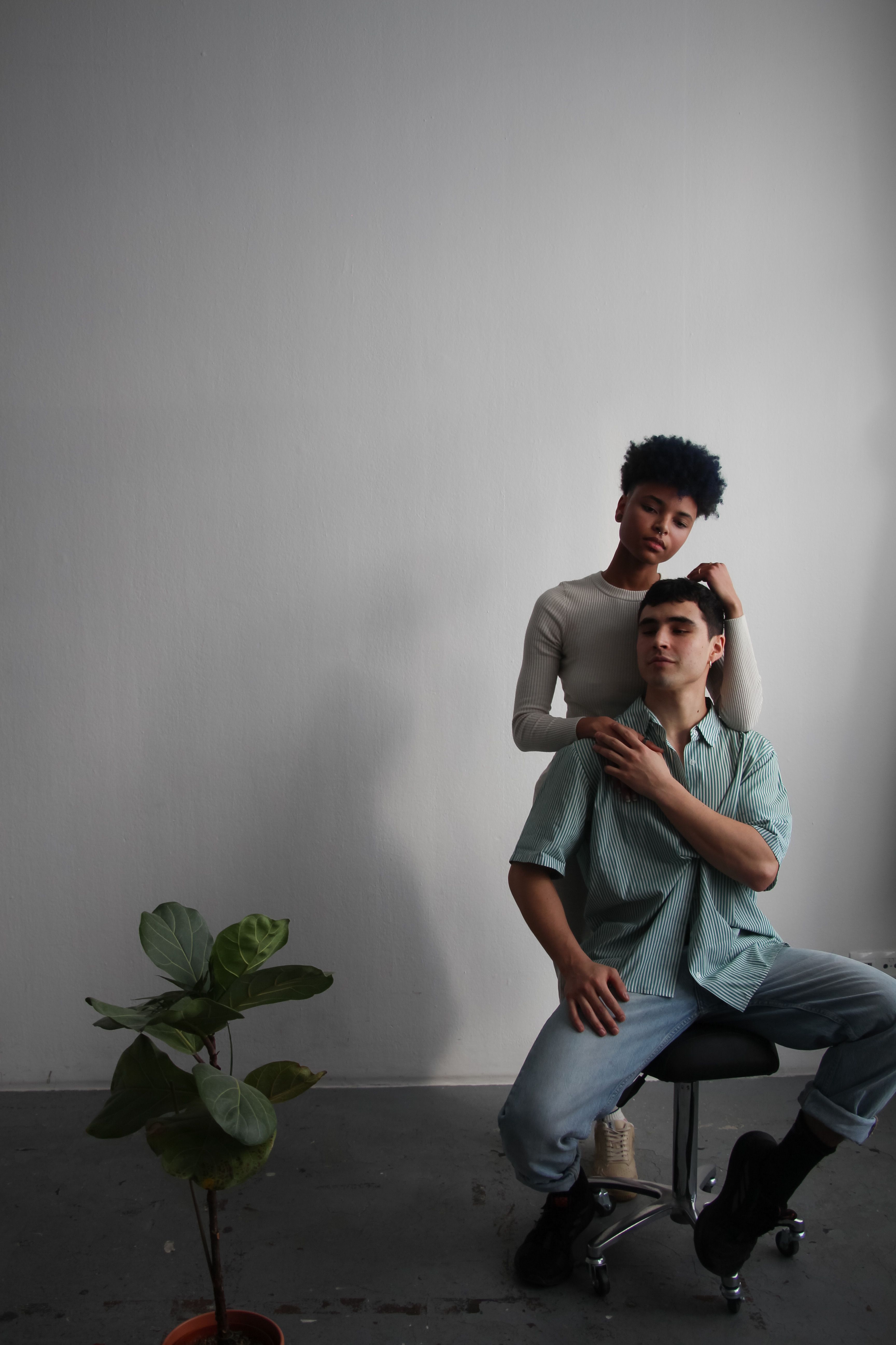 Two people sitting on a chair in front of a plant · Free Stock Photo
