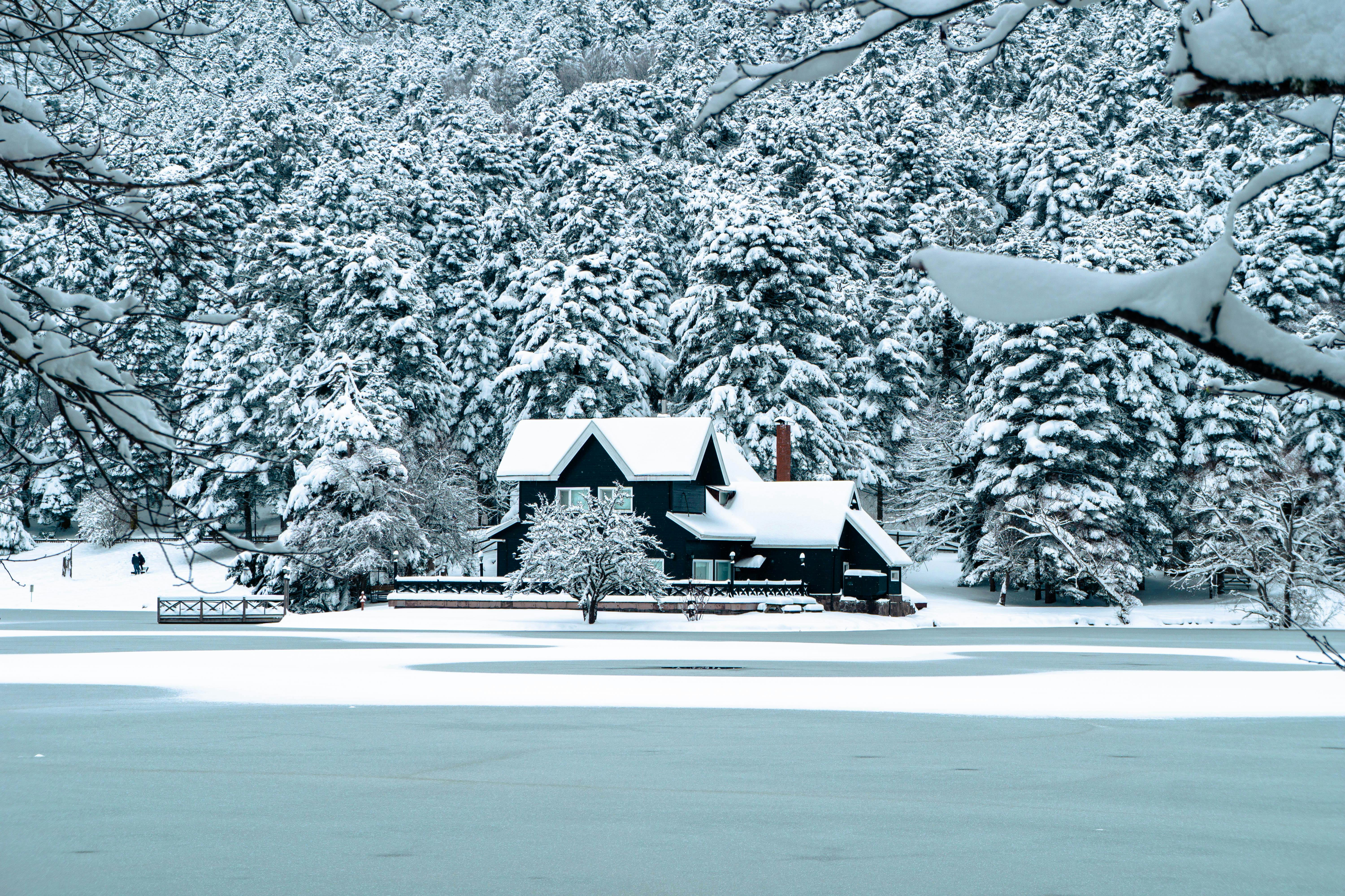 Snow-Covered House at the Foot of a Forested Hill · Free Stock Photo