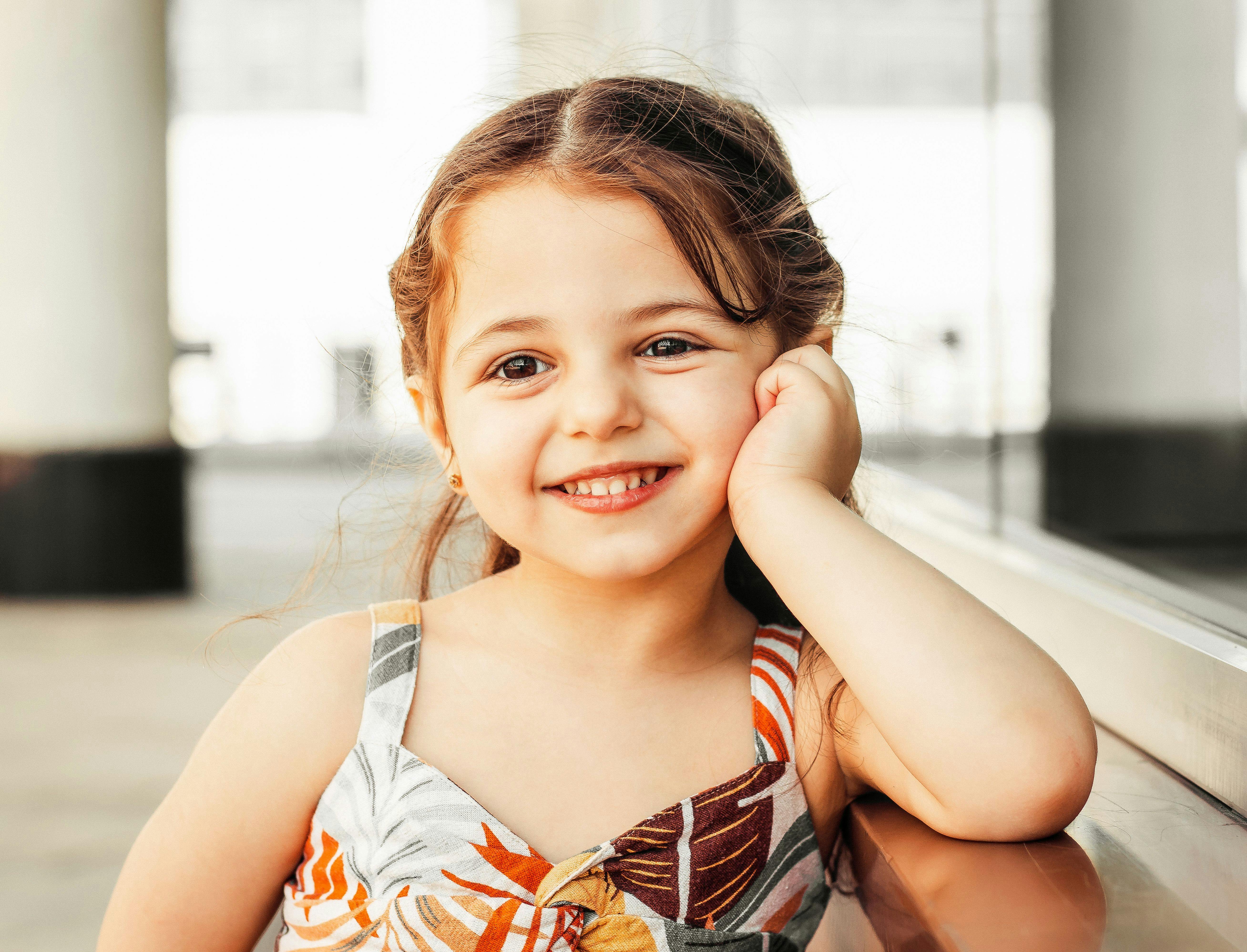 Small Girl in a Dress Leaning Against Her Arm · Free Stock Photo
