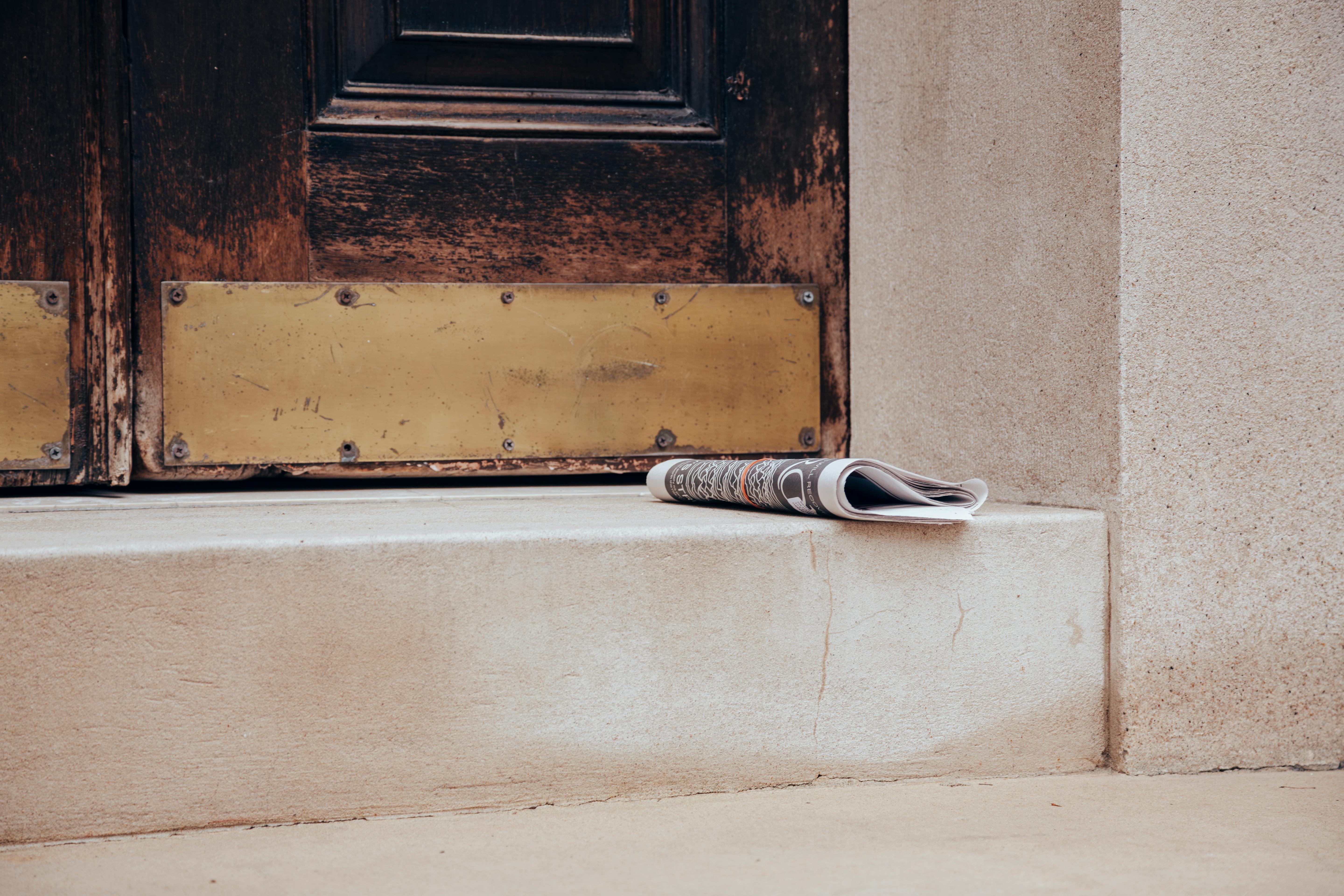 Newspaper Lying Down on Step by Door · Free Stock Photo