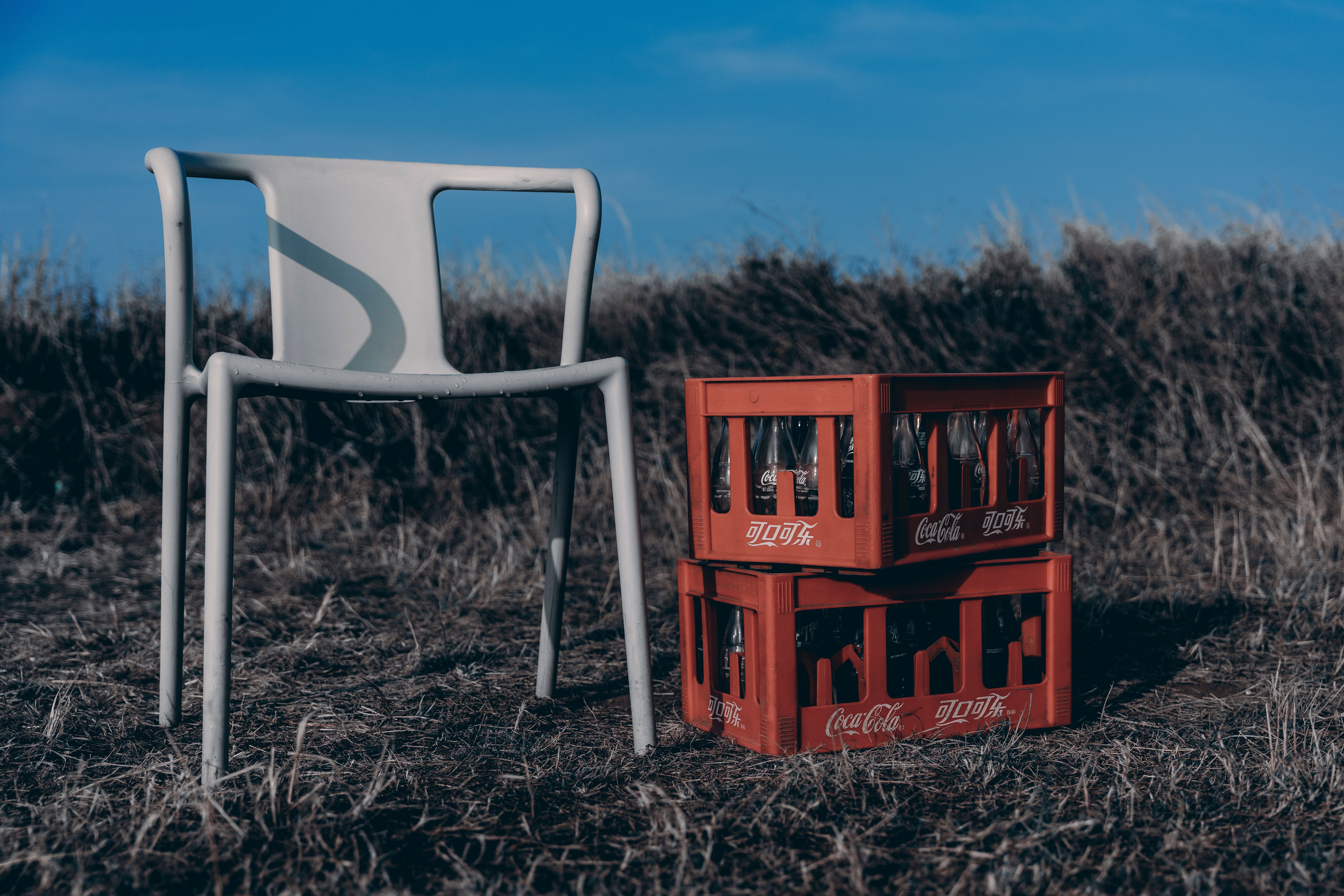 White Chair next to Coca Cola Boxes · Free Stock Photo