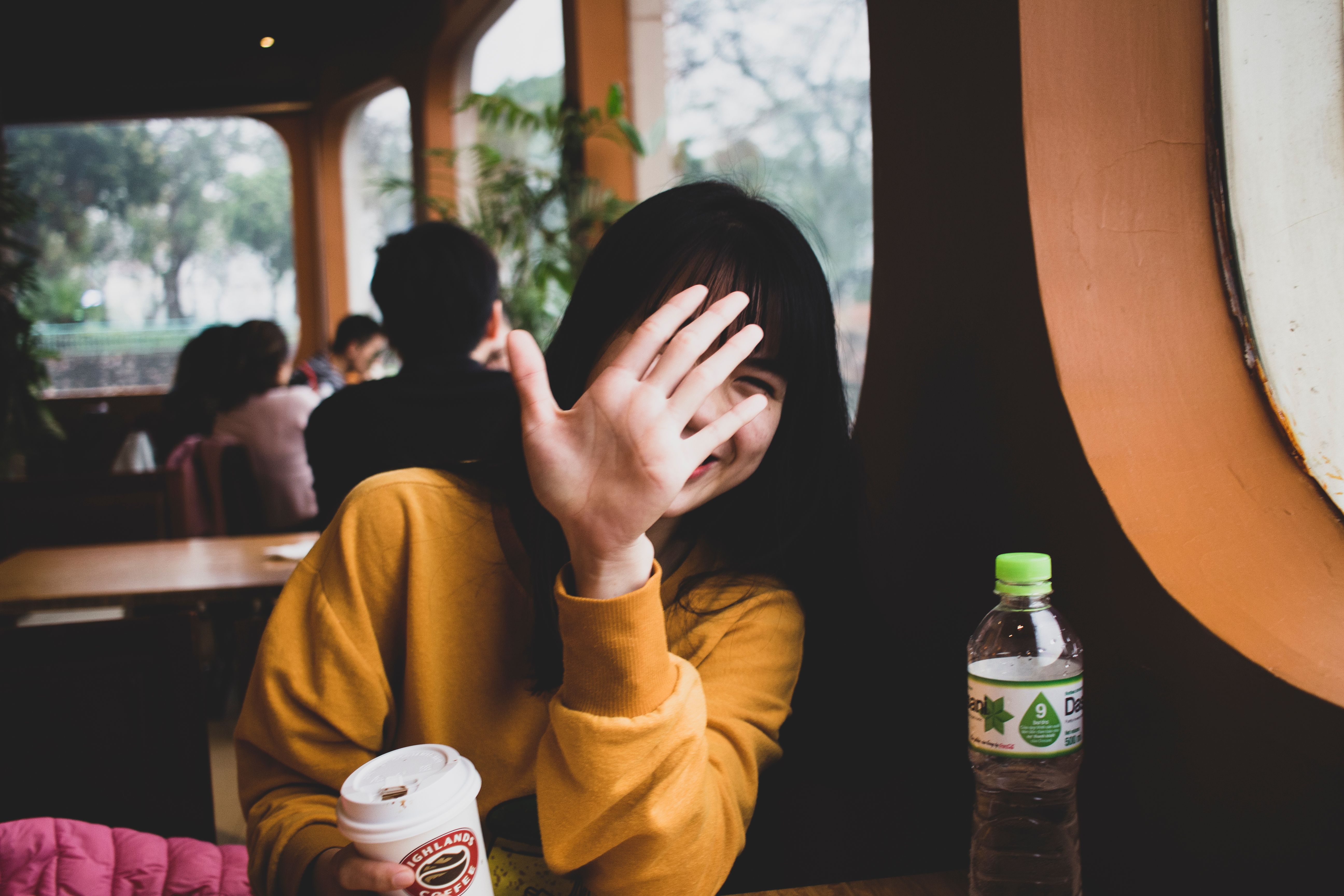 Portrait of a Shy Brunette Sitting at a Cafe Table · Free Stock Photo