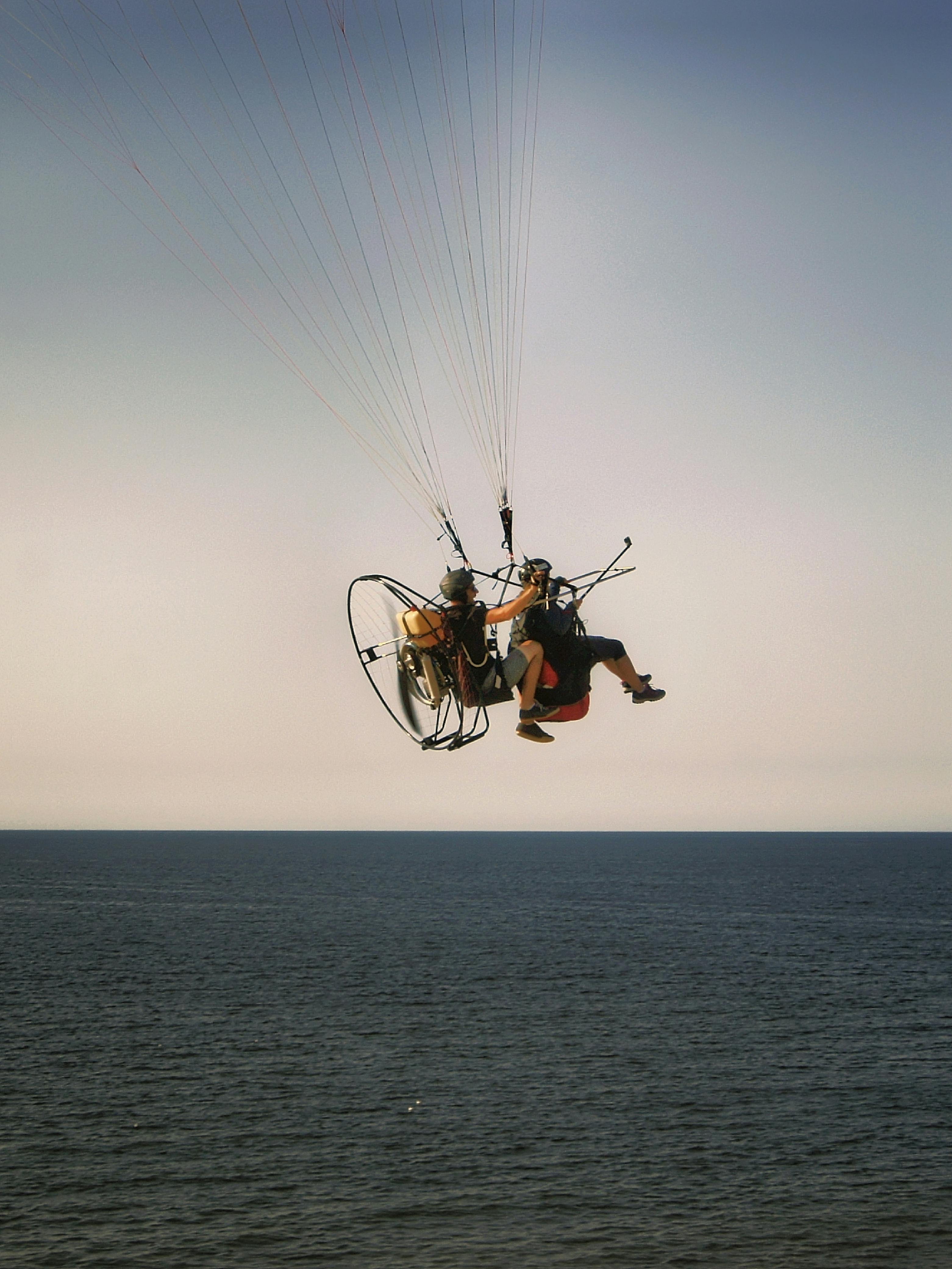 People Flying over Sea with Parachute · Free Stock Photo