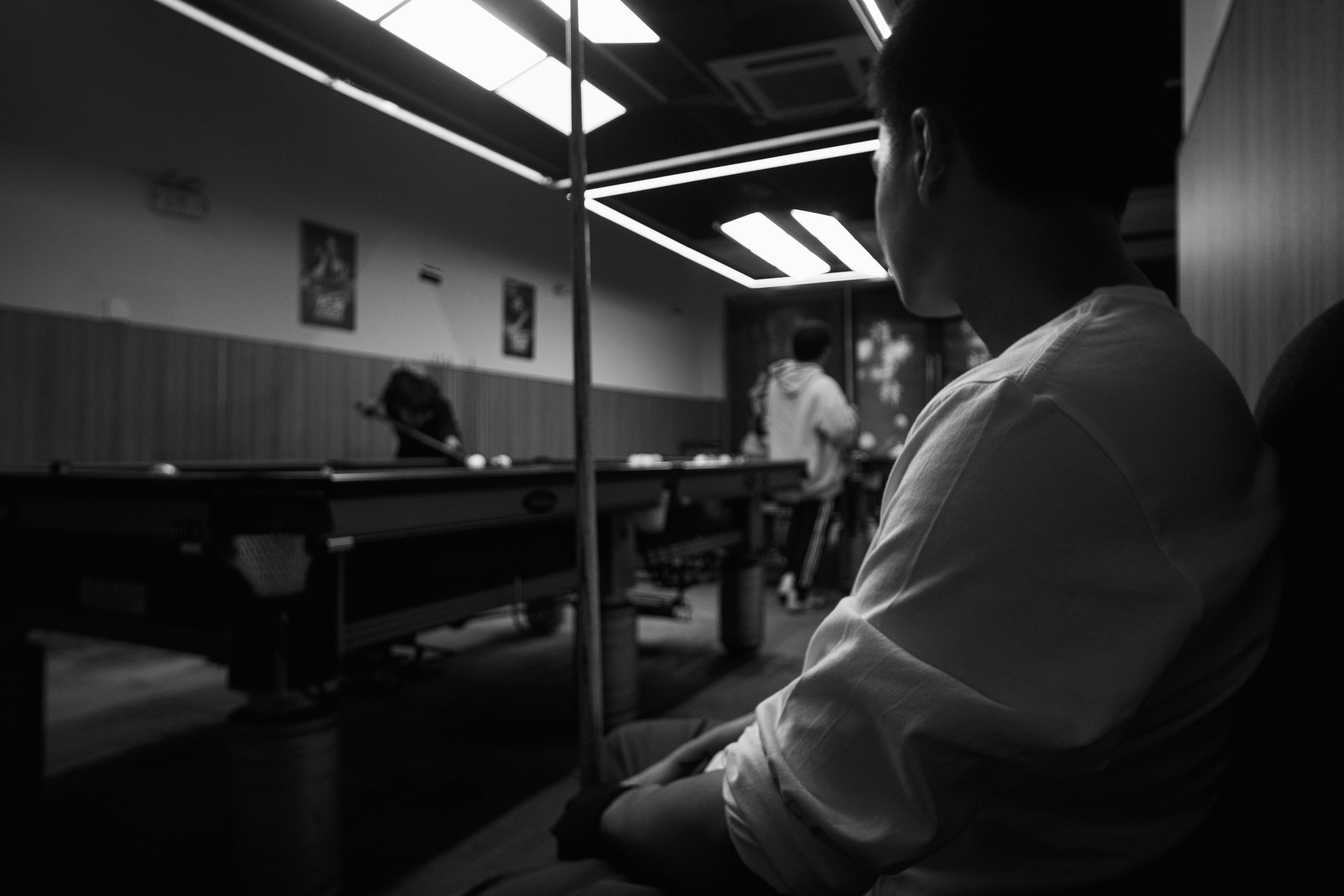 Man Sitting and People Playing Billiard behind · Free Stock Photo